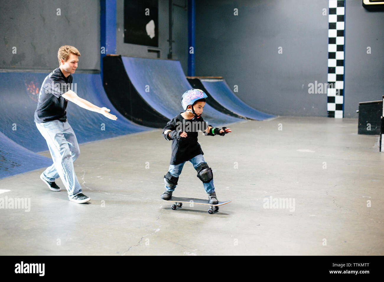 Skateboard instructor sends skater kid off on his own Stock Photo - Alamy
