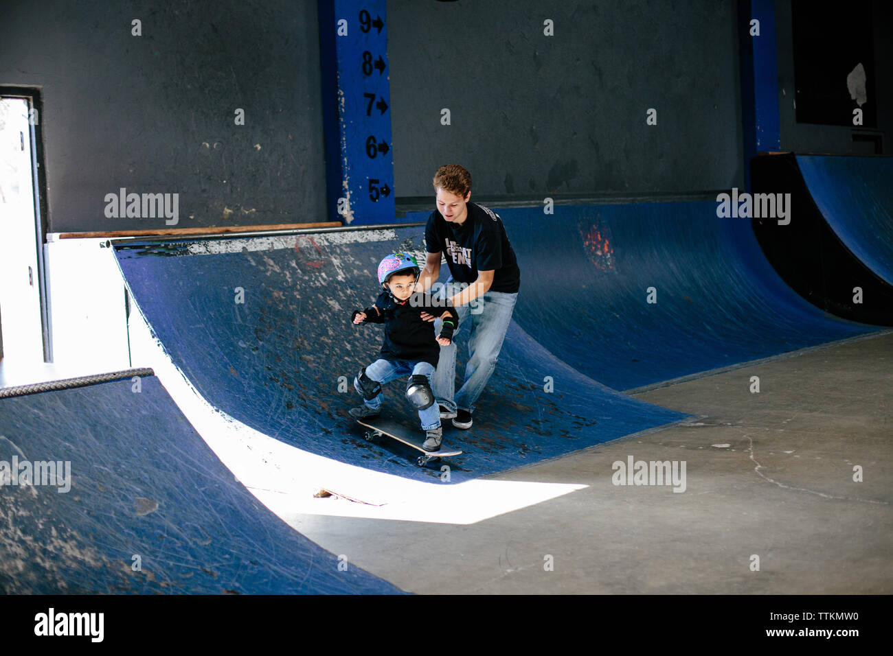 Skateboard instructor helps student skate down a ramp Stock Photo - Alamy