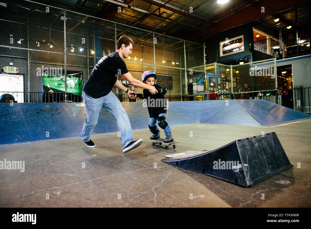 Skateboarding instructor holds hands and runs with student for a jump ...