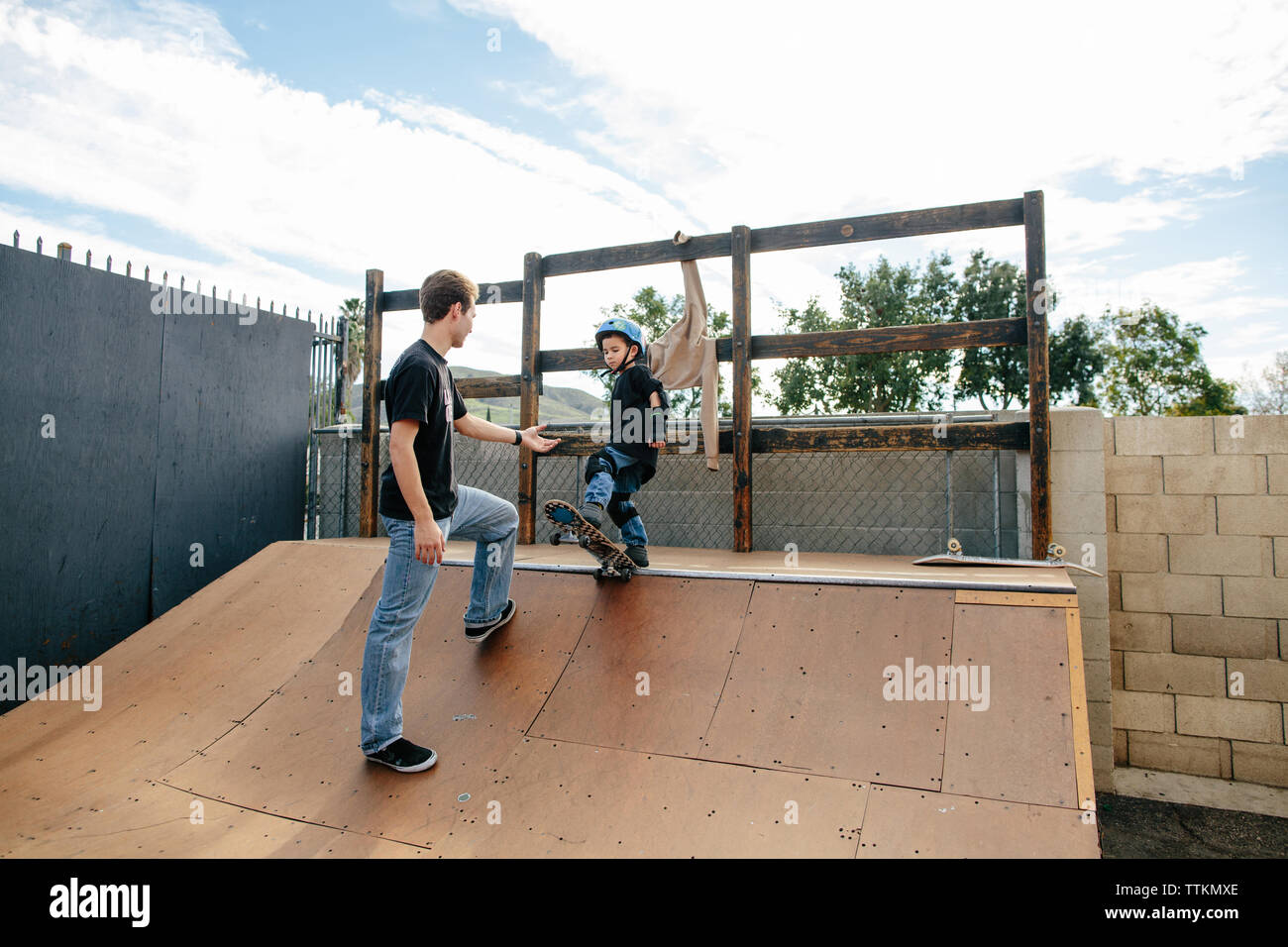 Skateboard instructor extends a hand to student on half pipe Stock ...
