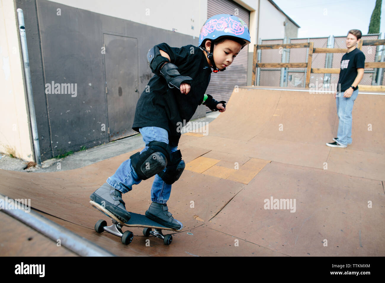 Skater boy riding a half pipe with instructor watching over Stock Photo ...