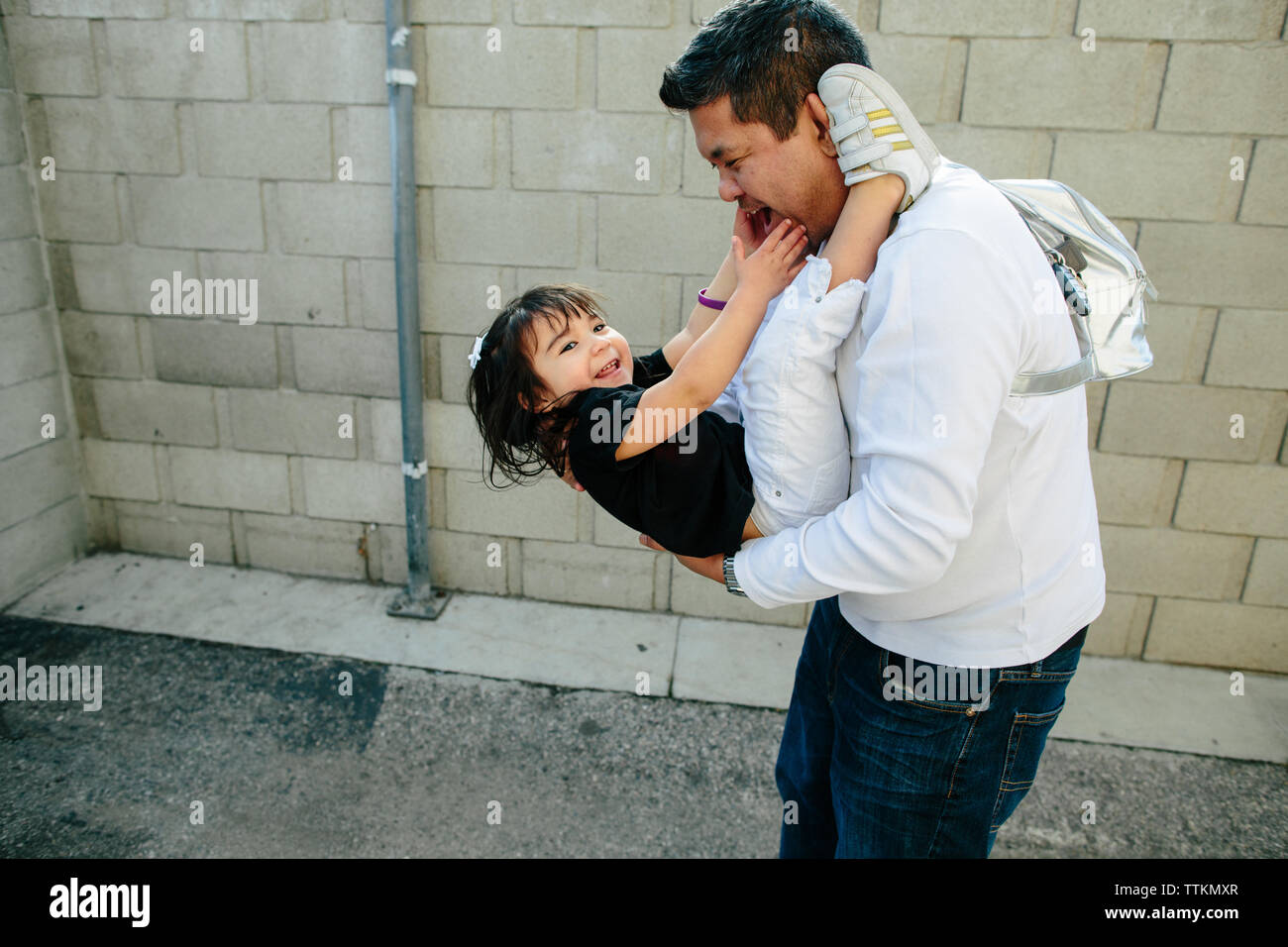 Father dips toddler daughter as she smiles at camera Stock Photo - Alamy