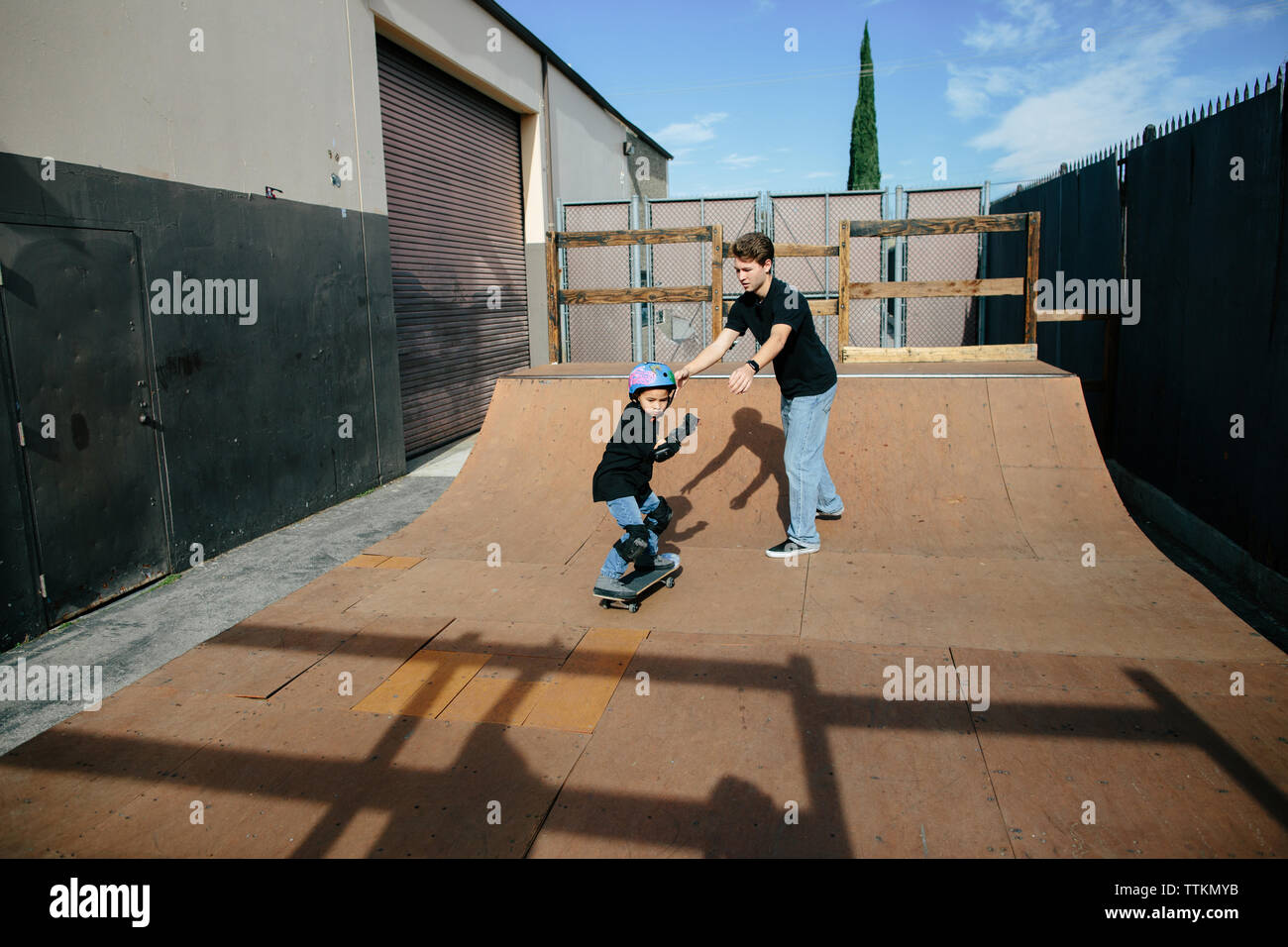 Skateboard instructor releases student on half pipe Stock Photo - Alamy