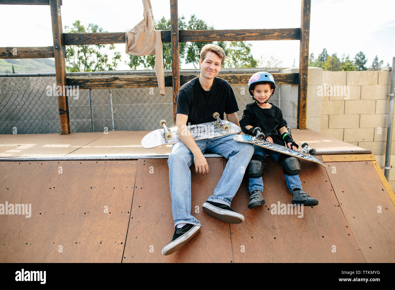 Young boy and skateboarding instructor smile for photo on half pipe ...
