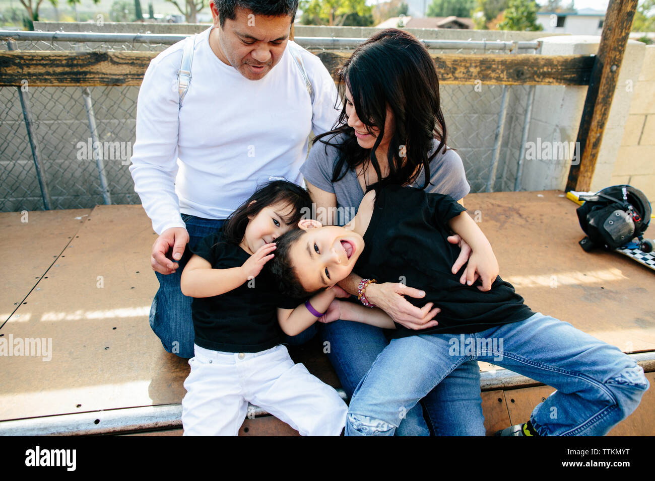 Children act silly while sitting on half pipe with their parents Stock ...