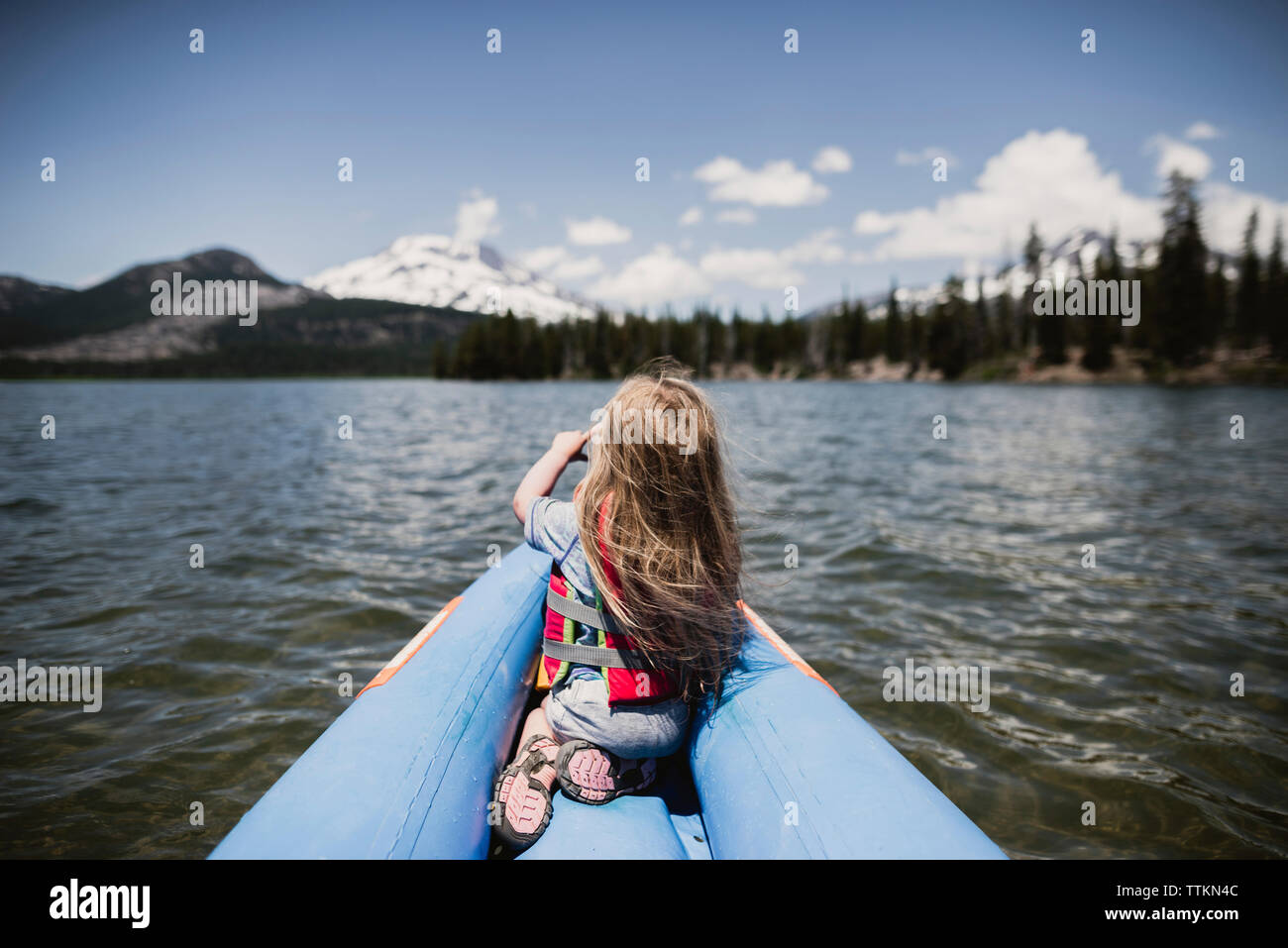 Rear view of girl sitting in inflatable raft on lake Stock Photo - Alamy