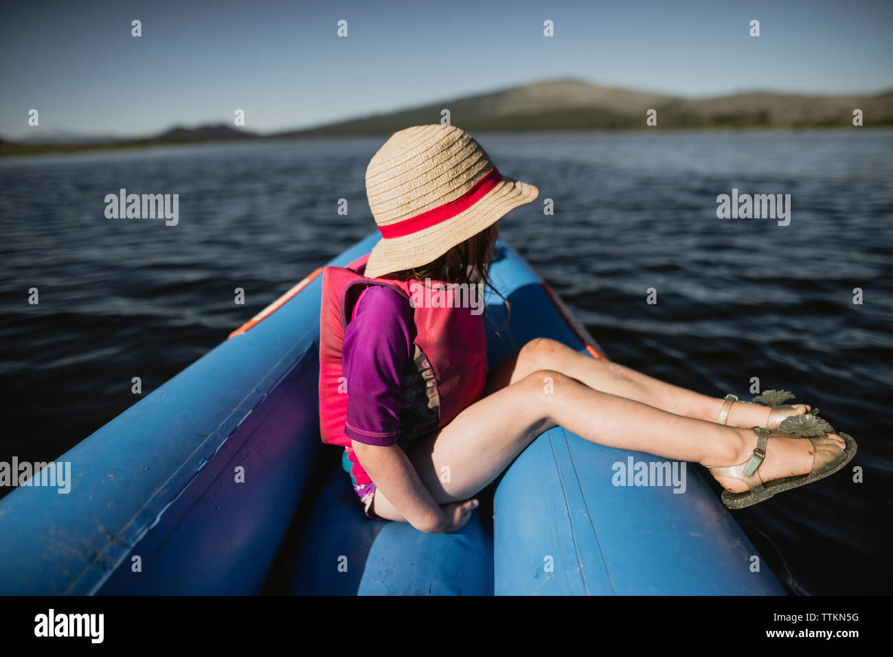 Side view of thoughtful girl wearing hat while sitting in inflatable ...