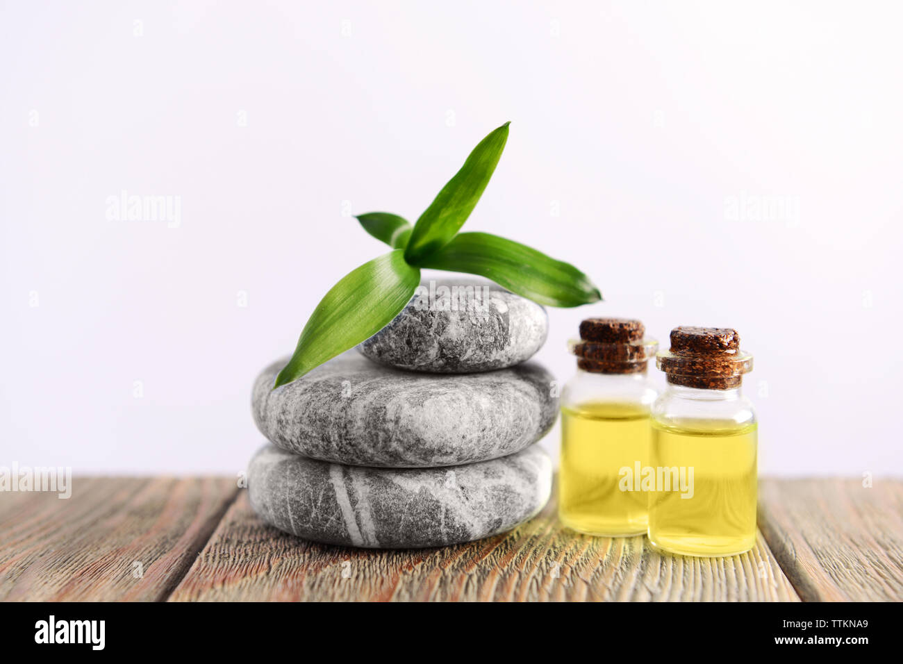 Gray spa stones with oil on light background Stock Photo - Alamy
