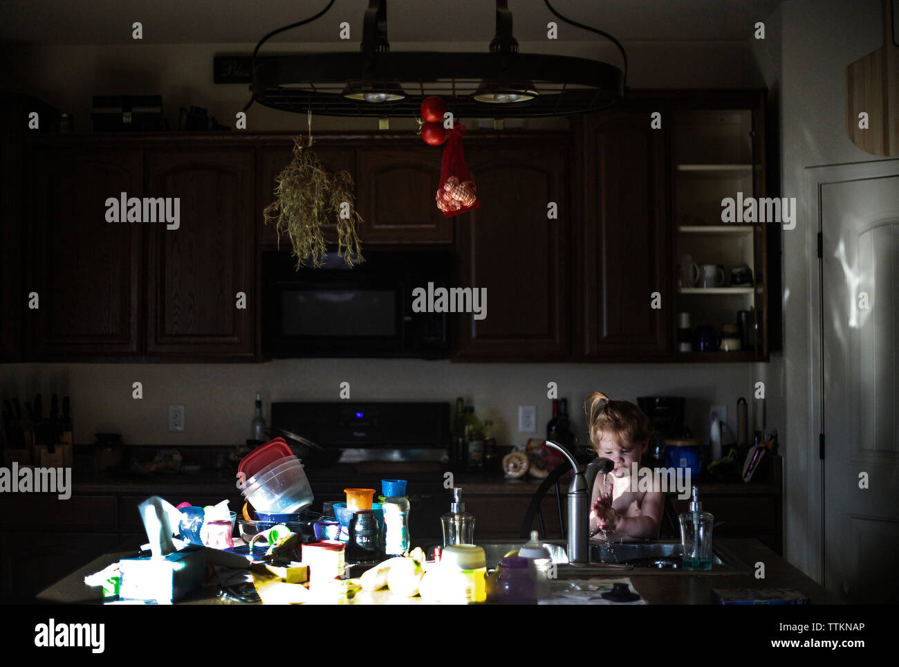 Girl washing hands in sink by messy table at kitchen Stock Photo - Alamy