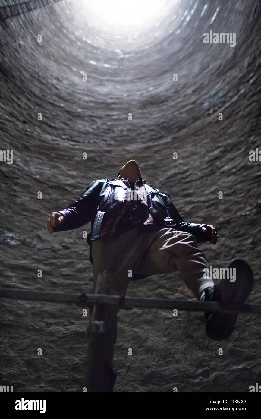 Low angle view of man looking up in empty well Stock Photo - Alamy