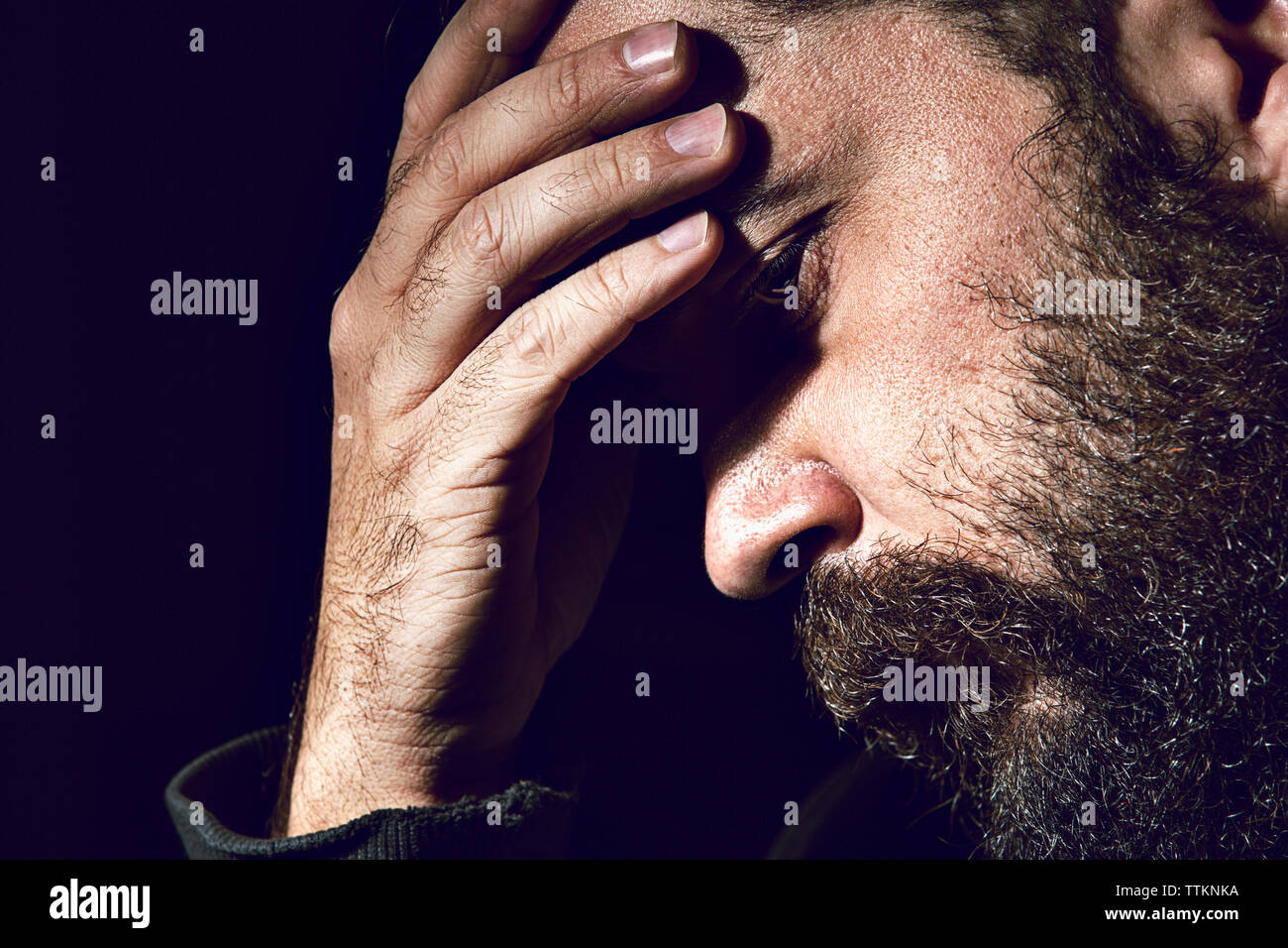Close-up of tensed man against black background Stock Photo - Alamy