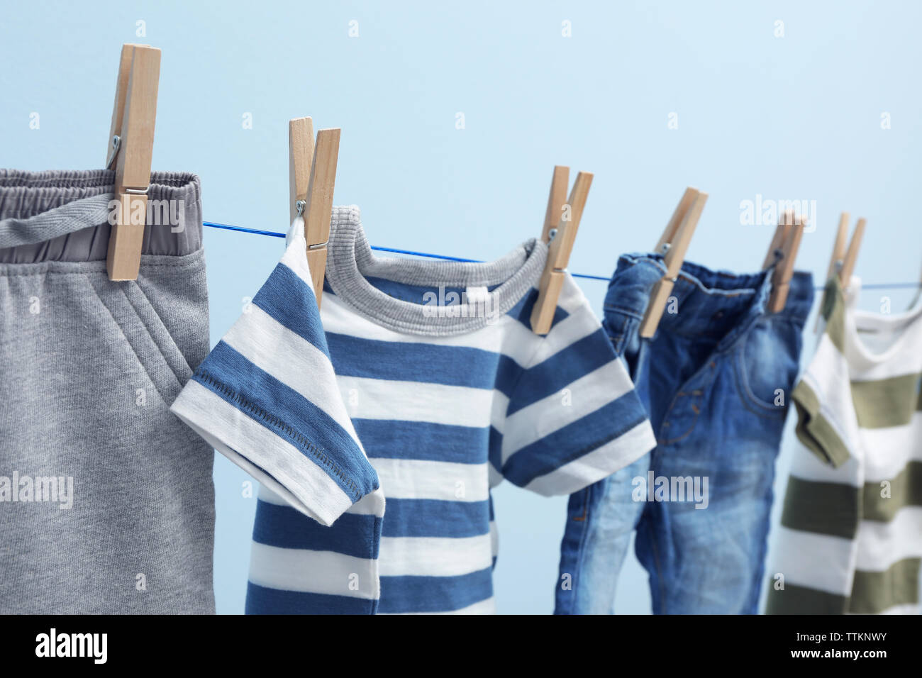 Baby clothes hanging on rope on grey background Stock Photo - Alamy