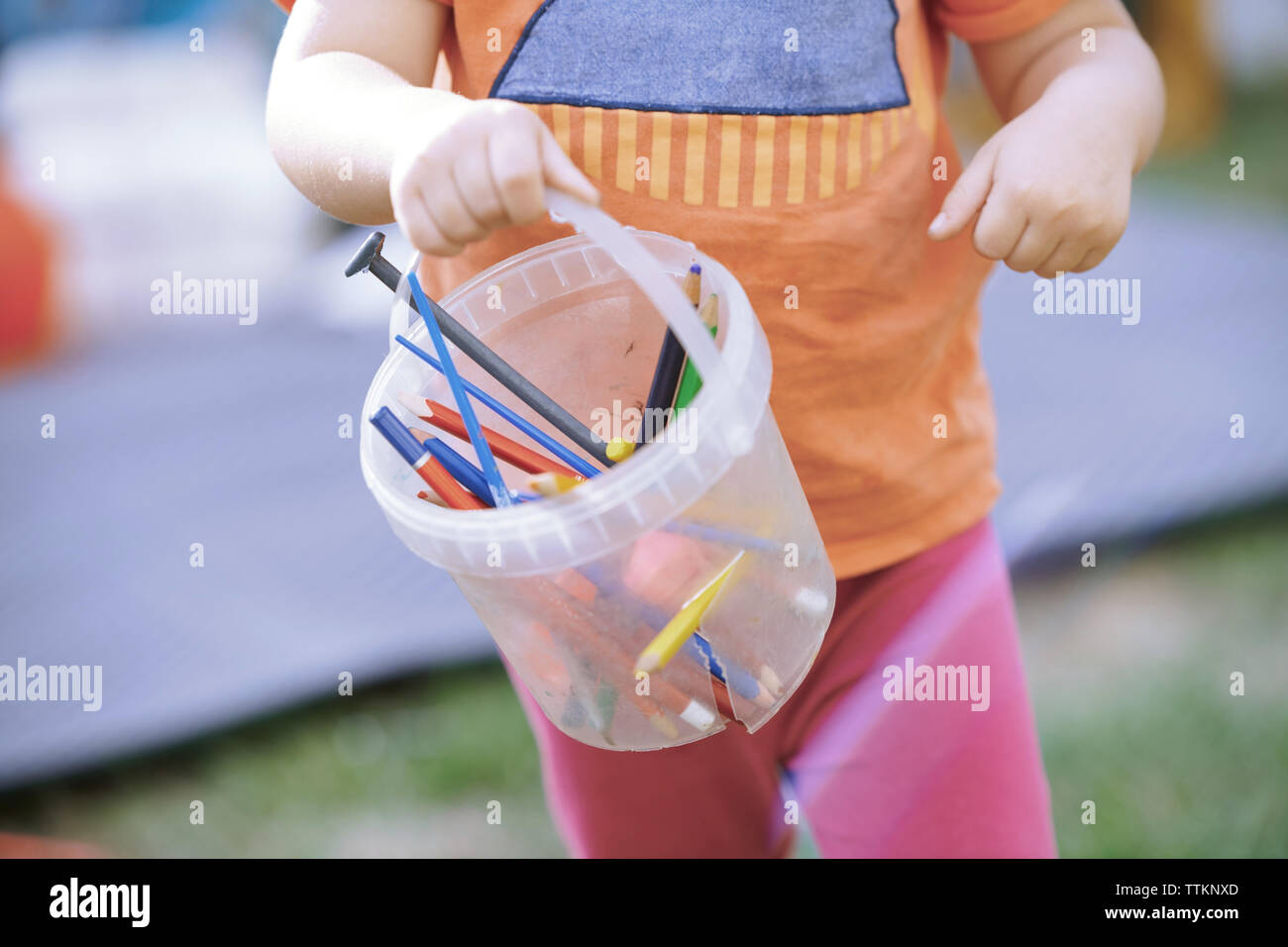 Little child carrying the bucket with colored pencils Stock Photo - Alamy