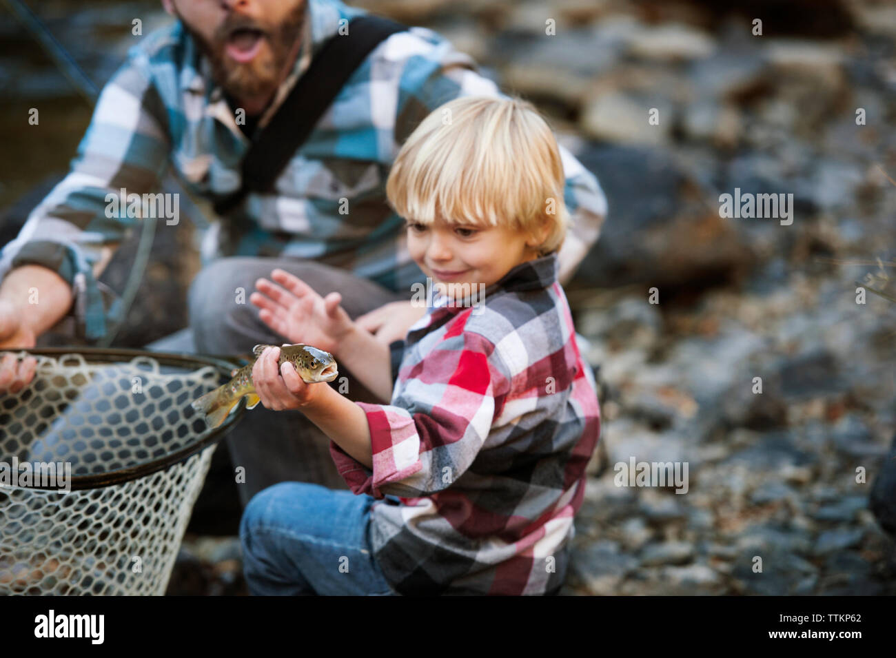 Boy holding fish while standing by father Stock Photo - Alamy