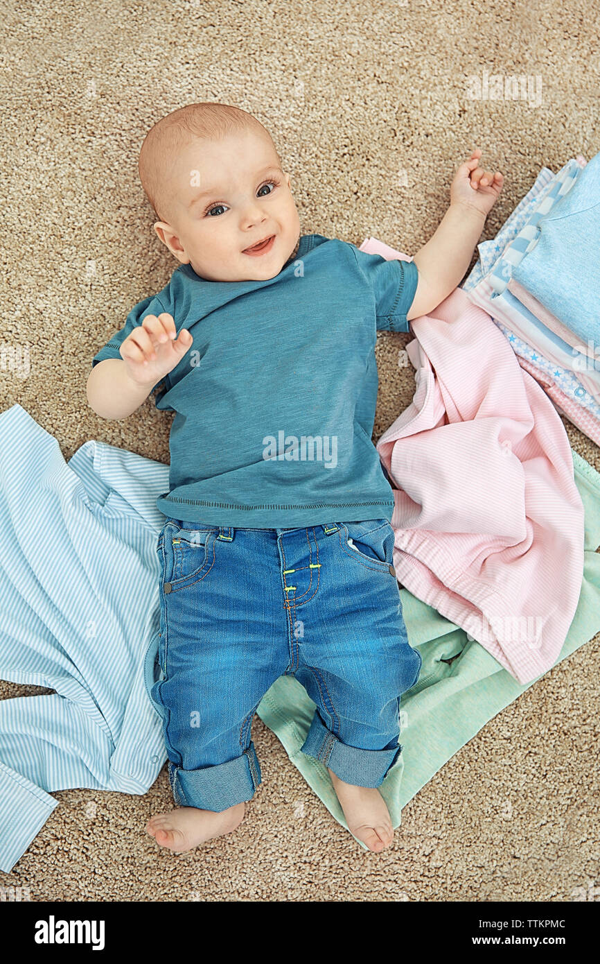 Smiling adorable baby with different clothes on the floor Stock Photo ...