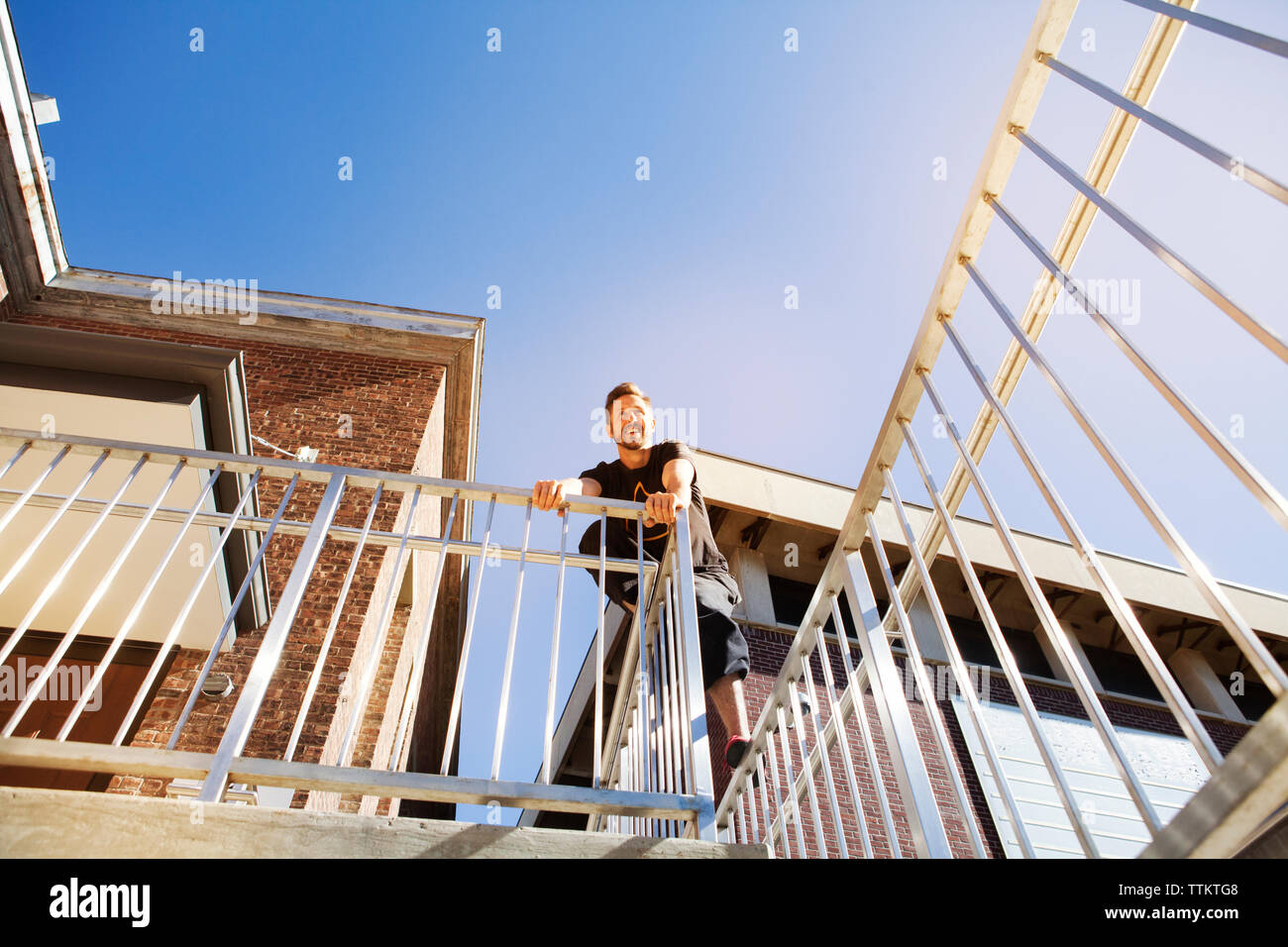 Low angle view of smiling man standing on building railing against ...
