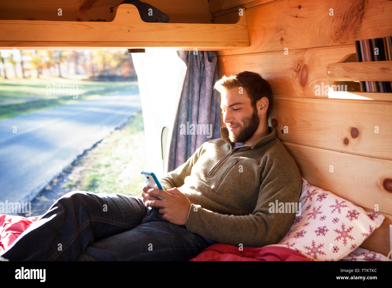 Man using smart phone while sitting on bed in camper van Stock Photo ...