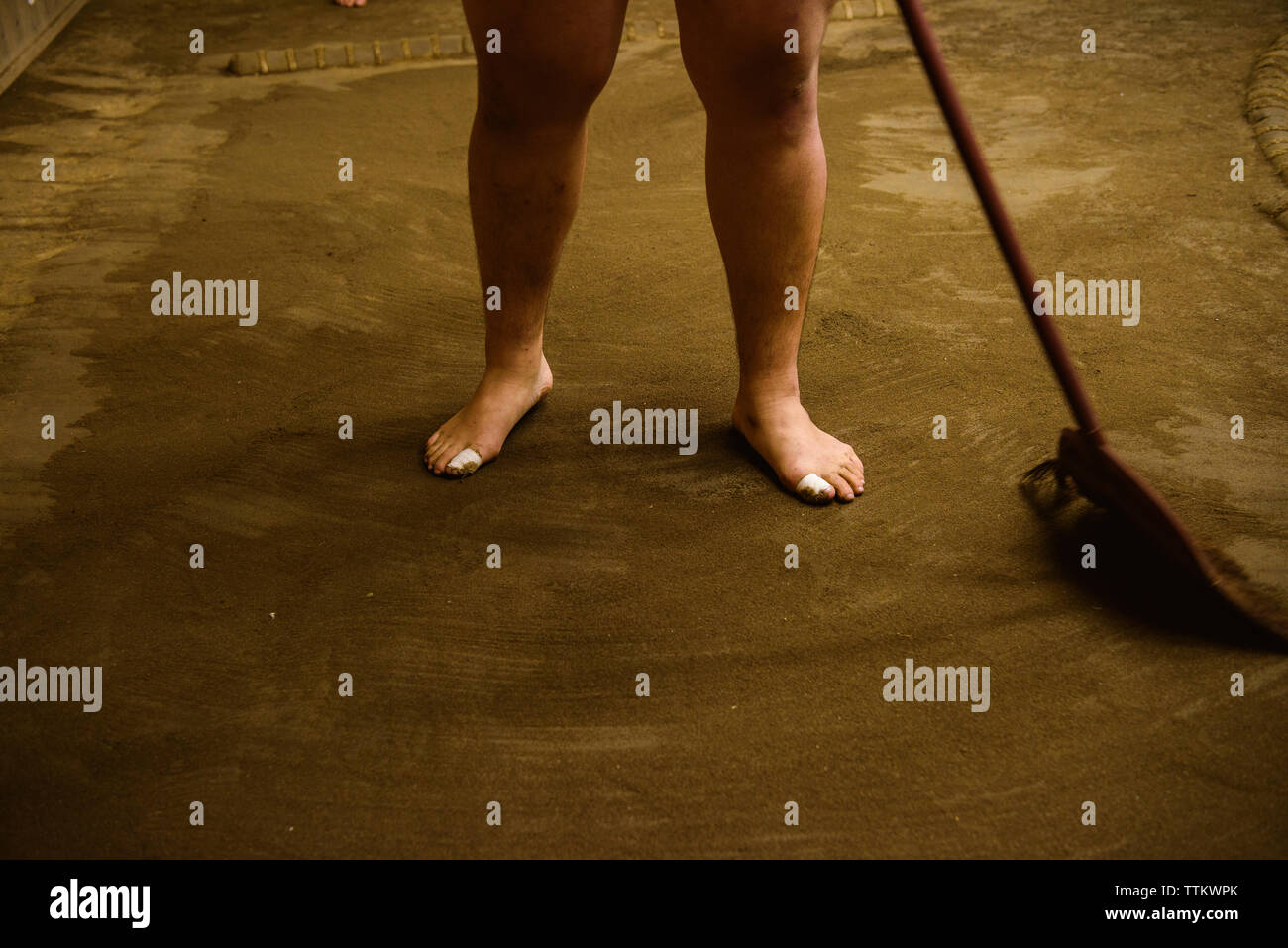 Low section of wrestler sweeping field with broom in sumo beya Stock ...