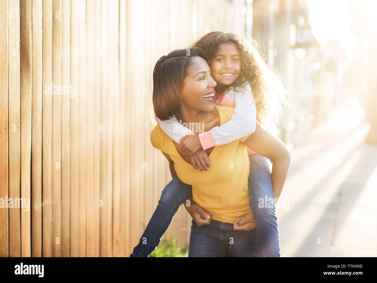 Happy mother giving piggyback ride to daughter during sunny day Stock ...