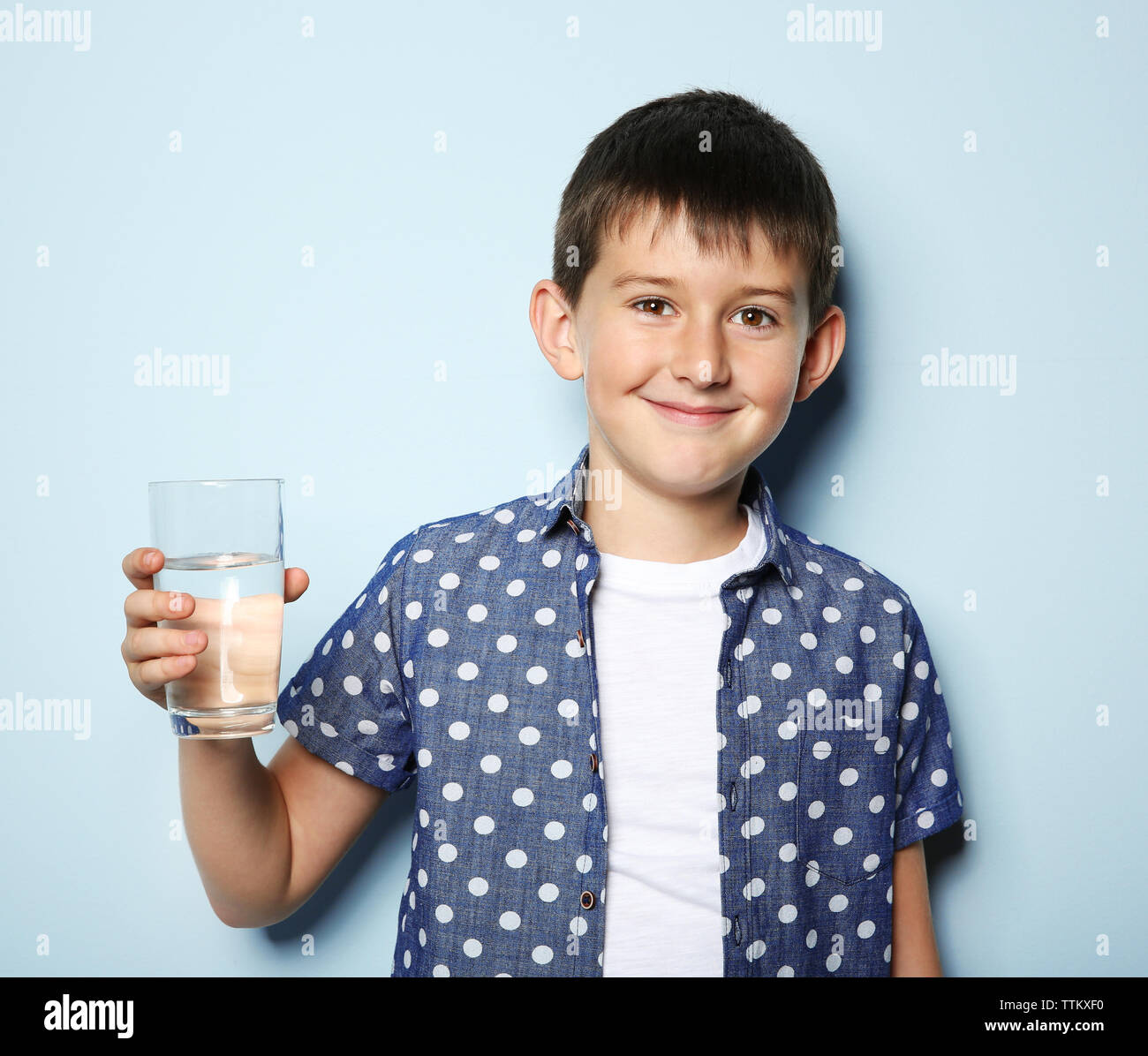 Cute boy drinking water on light background Stock Photo - Alamy