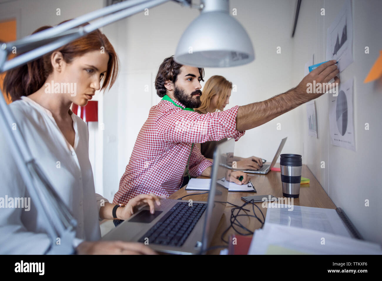 Side view of business people working at desk in creative office Stock ...