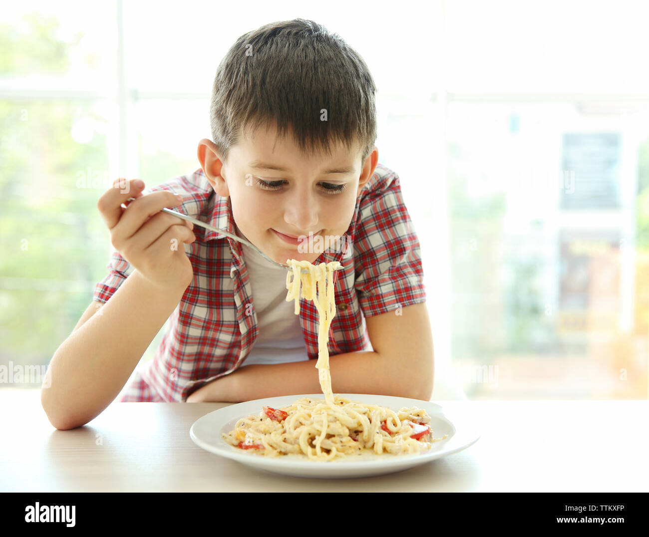Cute boy eating spaghetti on kitchen Stock Photo - Alamy