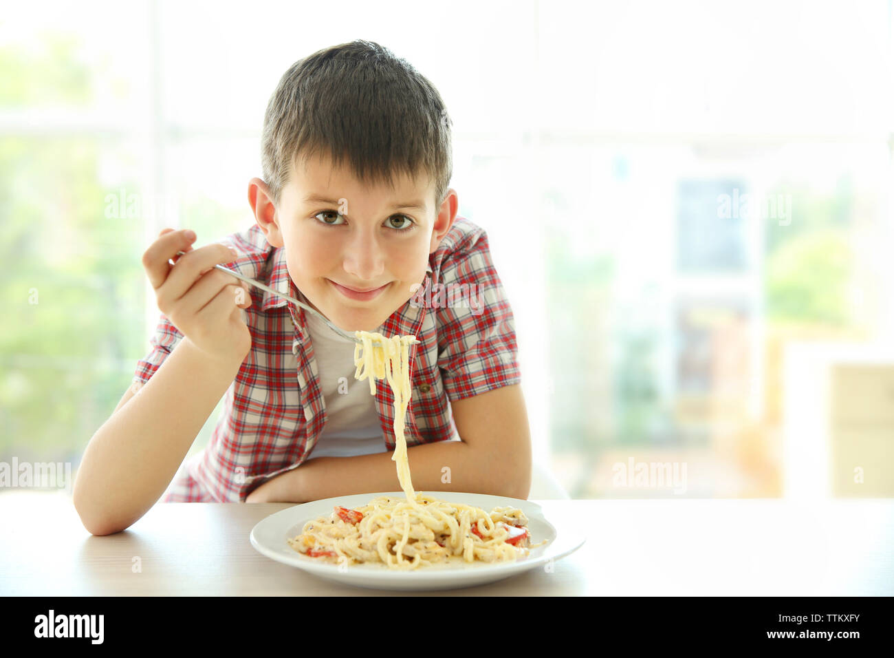 Cute boy eating spaghetti on kitchen Stock Photo - Alamy