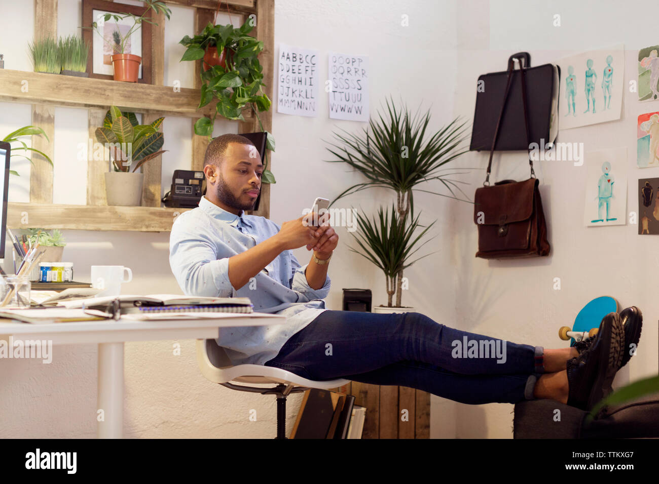 Full length of creative businessman using smart phone while sitting ...