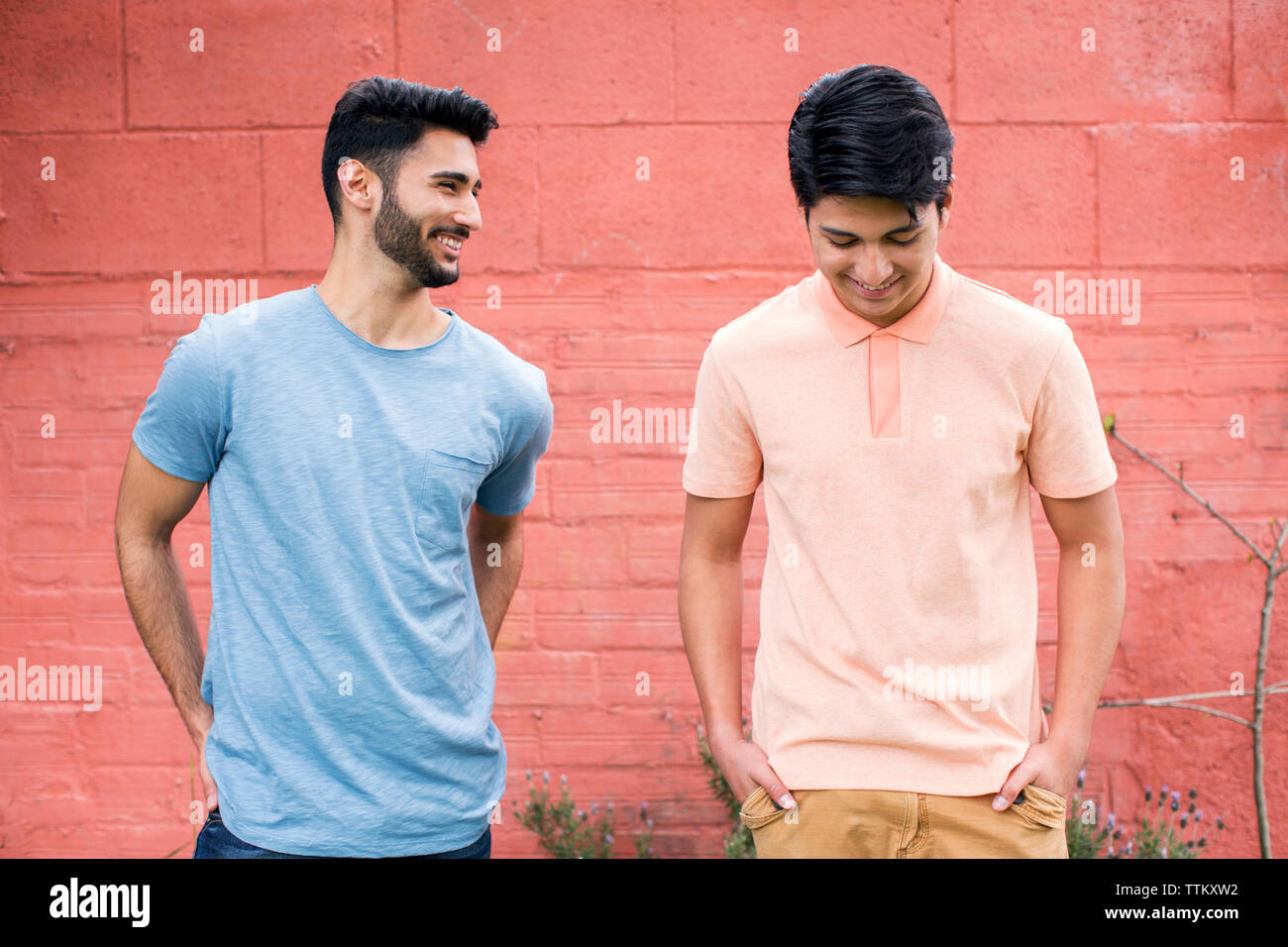 Happy male friends standing against wall Stock Photo - Alamy