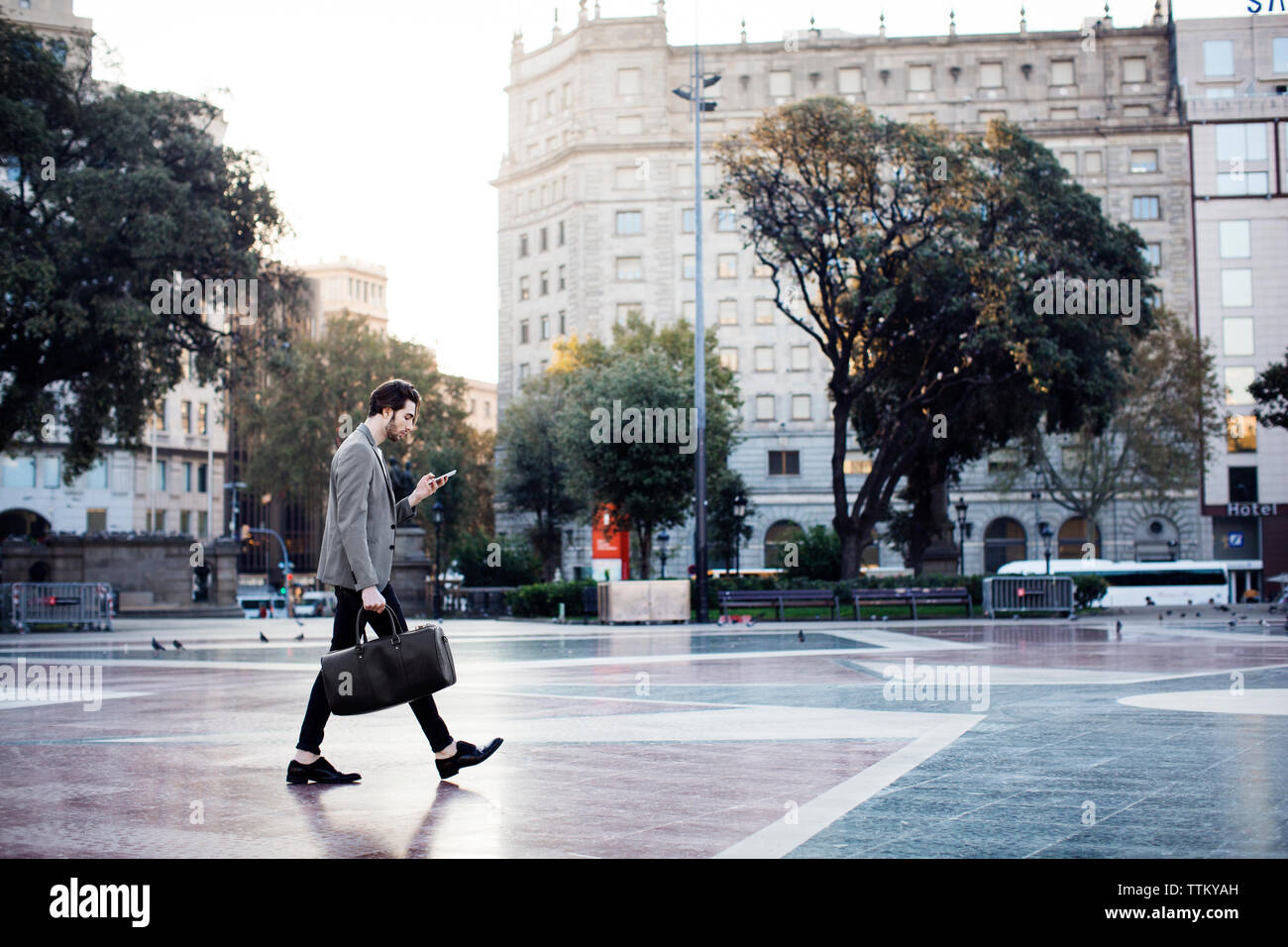 Man using mobile phone while walking on pavement Stock Photo - Alamy