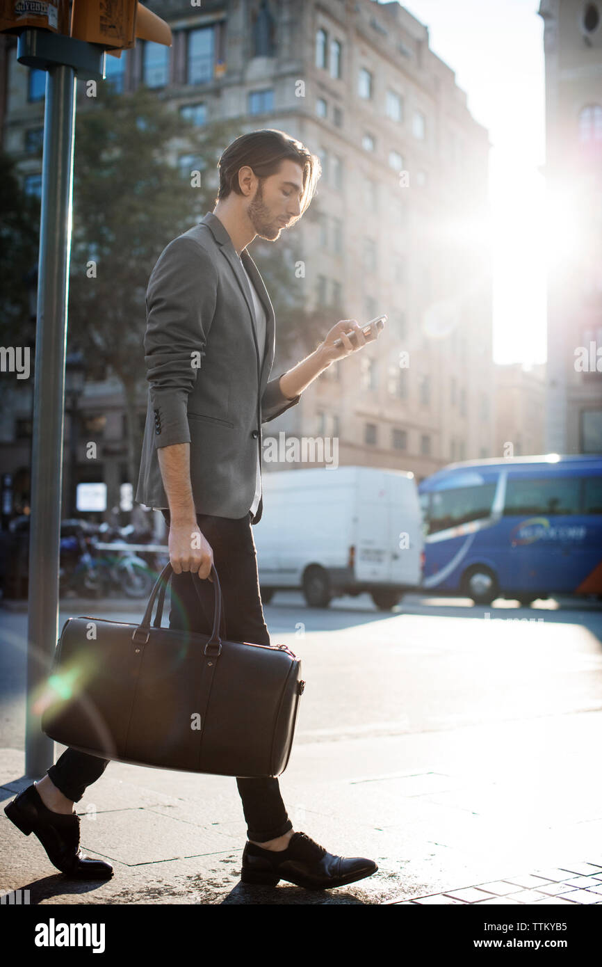 Man using mobile phone while walking on city street Stock Photo - Alamy