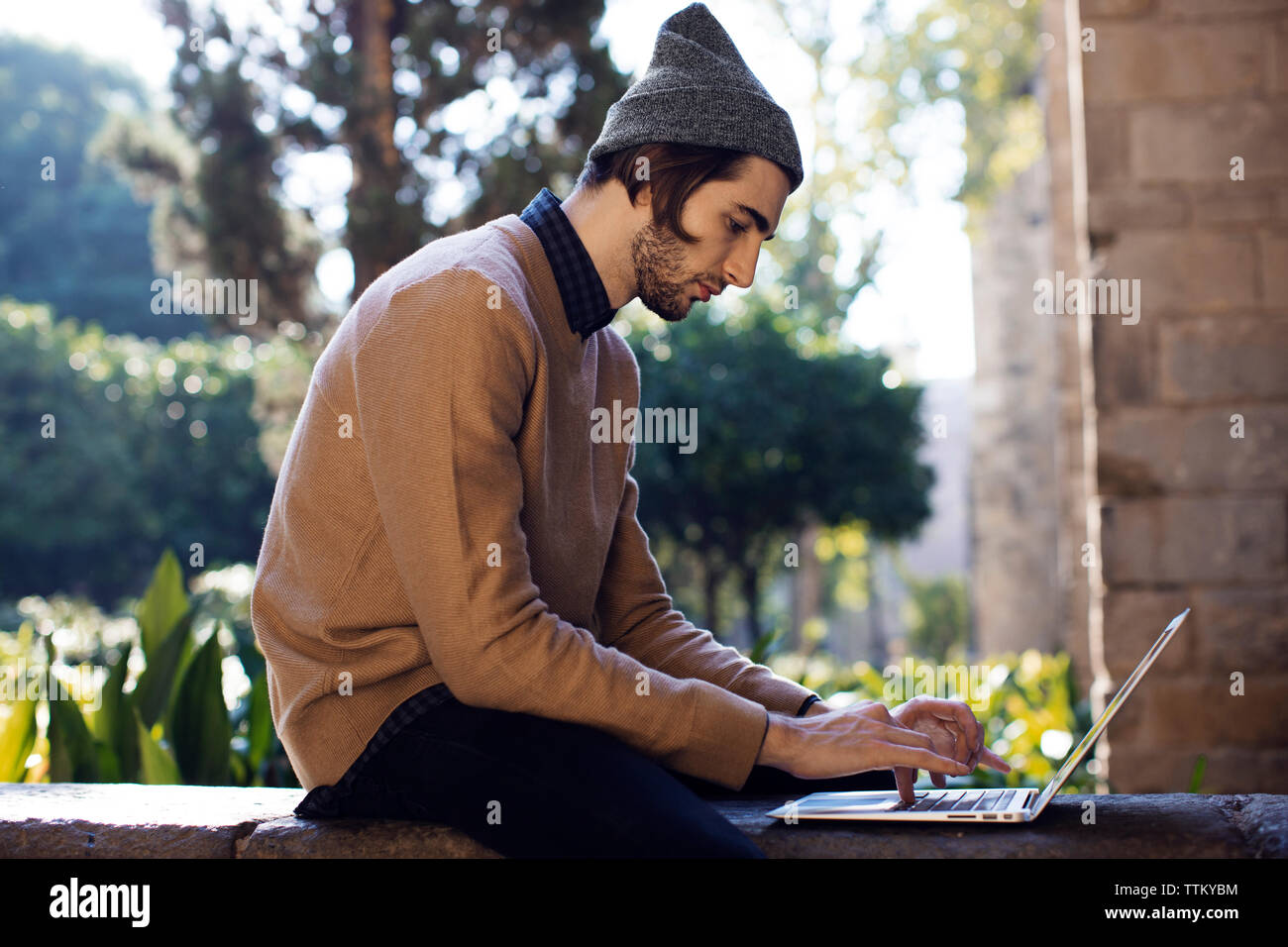 Side view of man using laptop computer retaining wall Stock Photo - Alamy