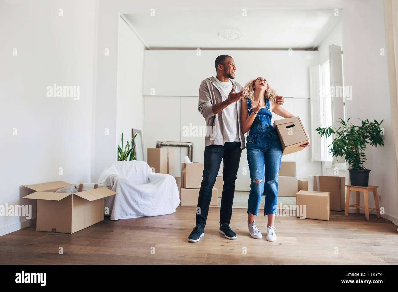 Full length of couple laughing while standing in new home Stock Photo ...