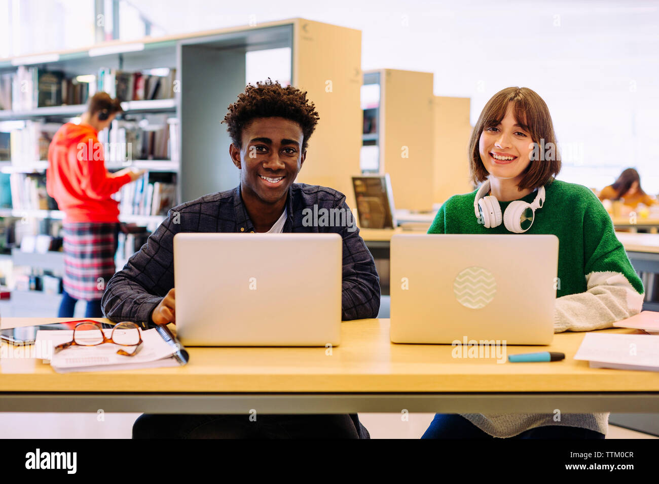 Portrait of friends studying through laptop computers in library Stock ...