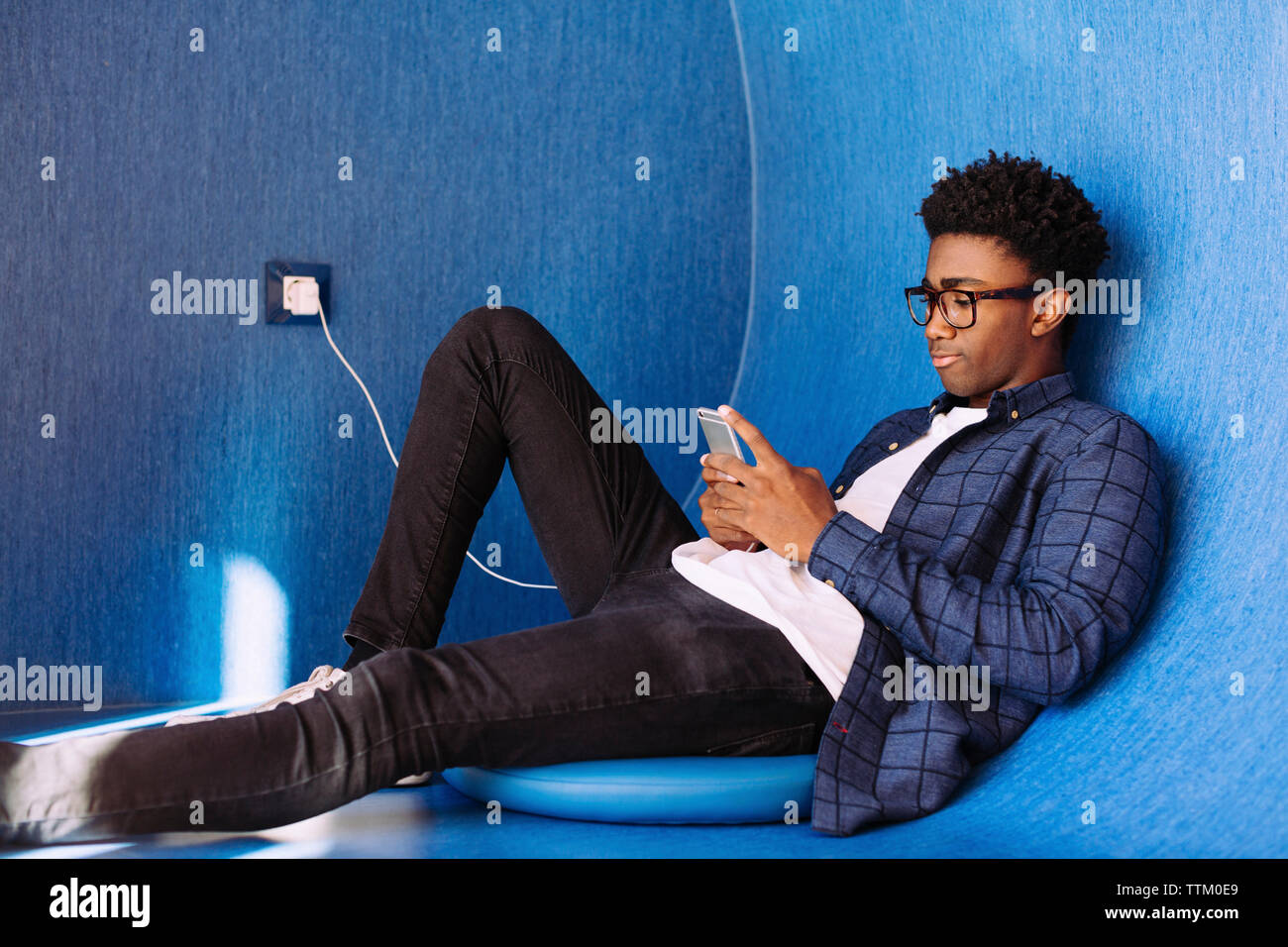 Man using mobile phone while sitting in library Stock Photo - Alamy