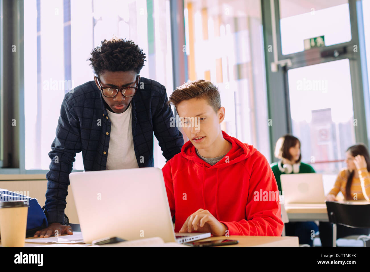 Friends discussing over laptop computers in library Stock Photo - Alamy