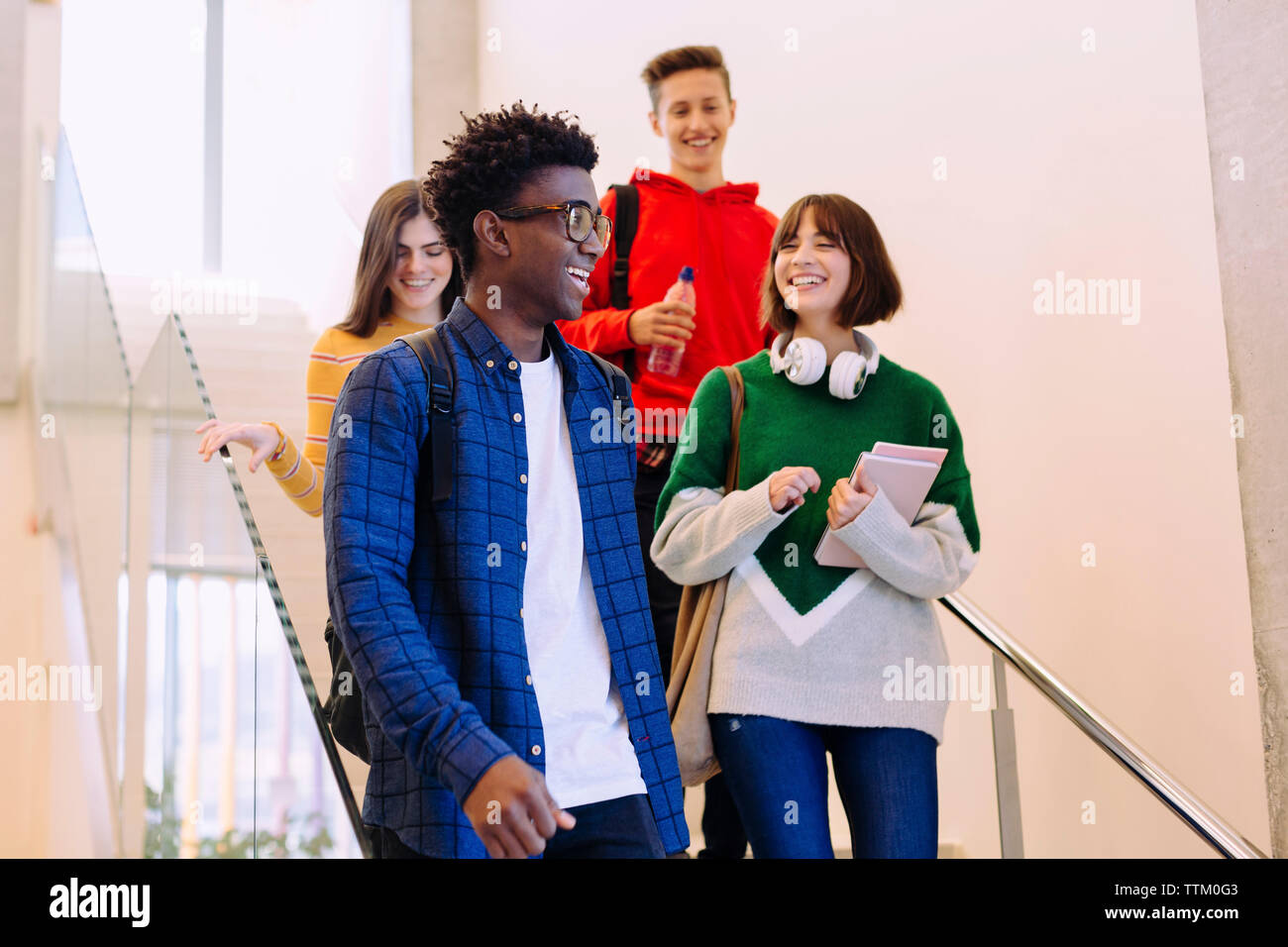 Low angle view of friends talking while moving down on steps at library ...