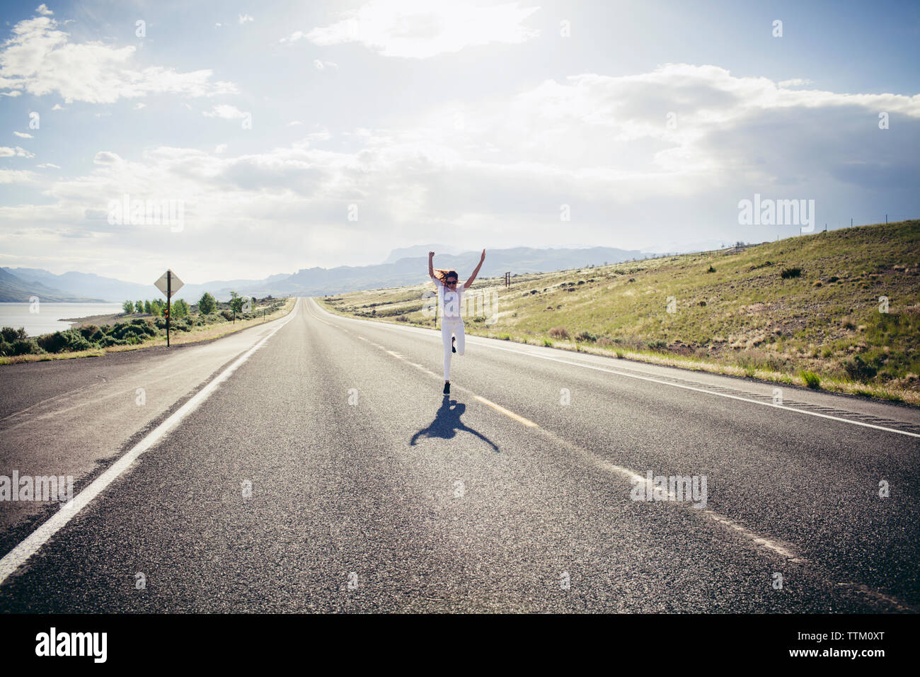 Happy woman running with arms raised on street in sunny day Stock Photo ...