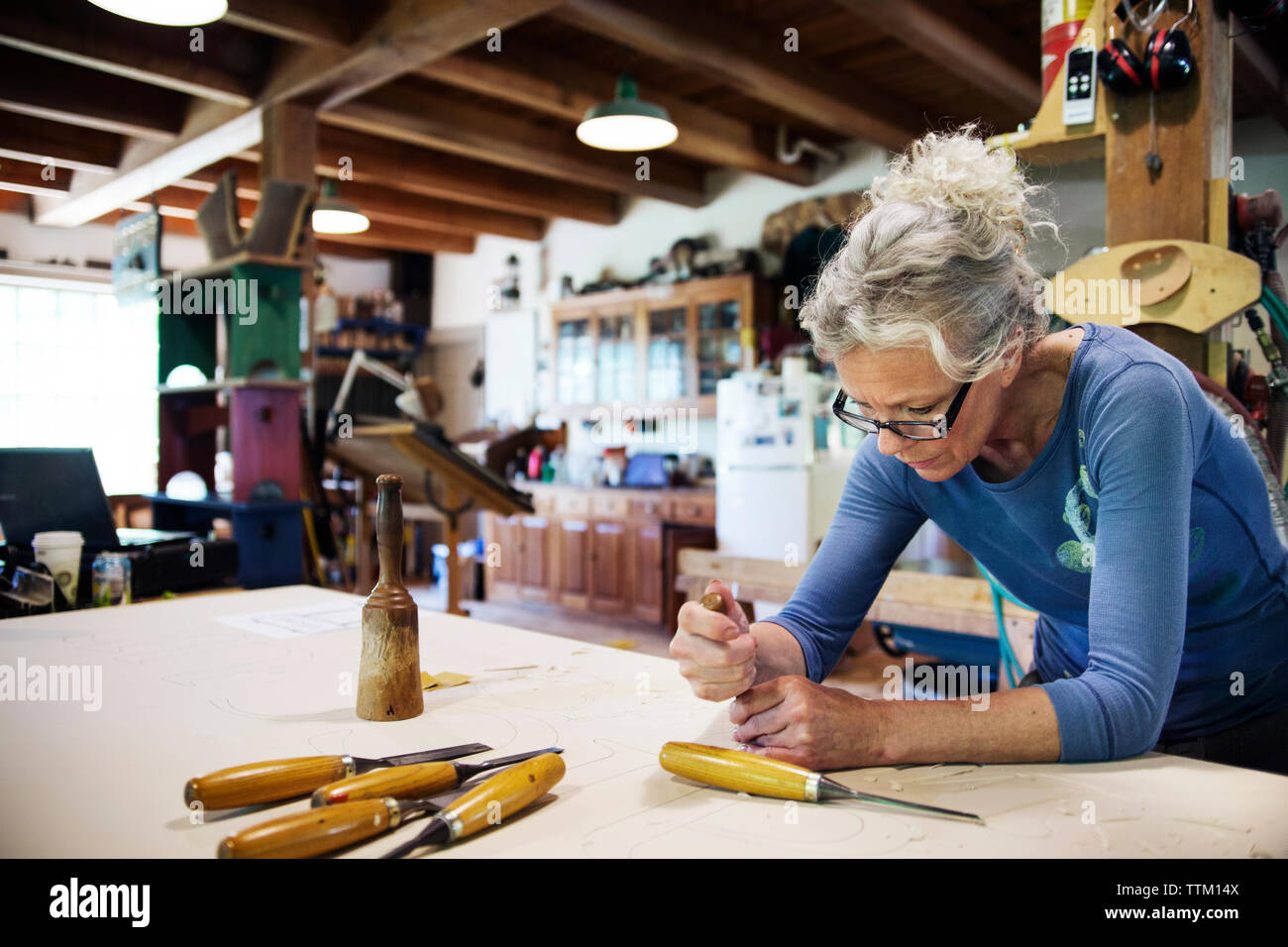 Concentrated female using chisel for shaping wood in workshop Stock ...