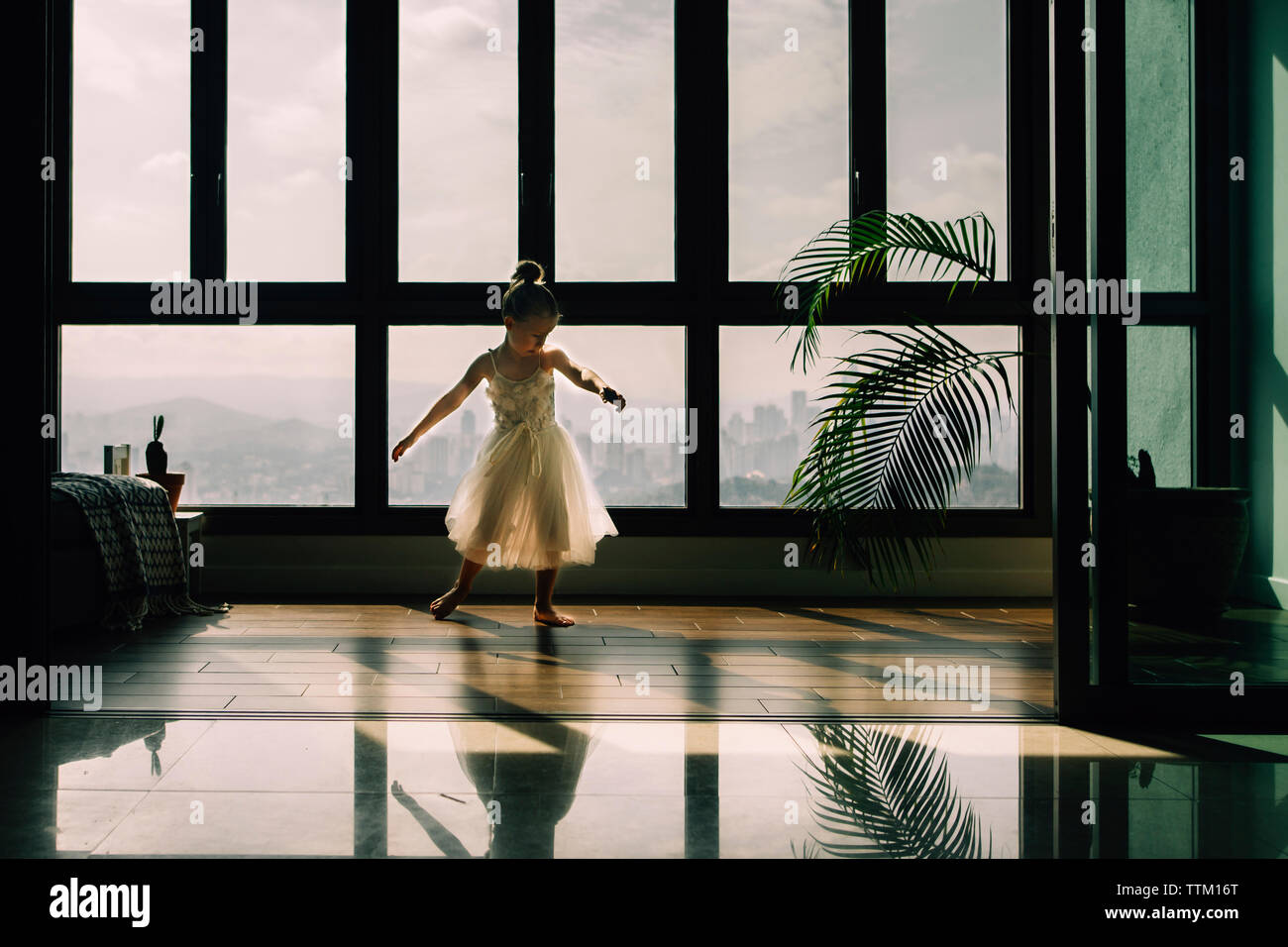 Full length of girl practicing ballet against window at home Stock ...