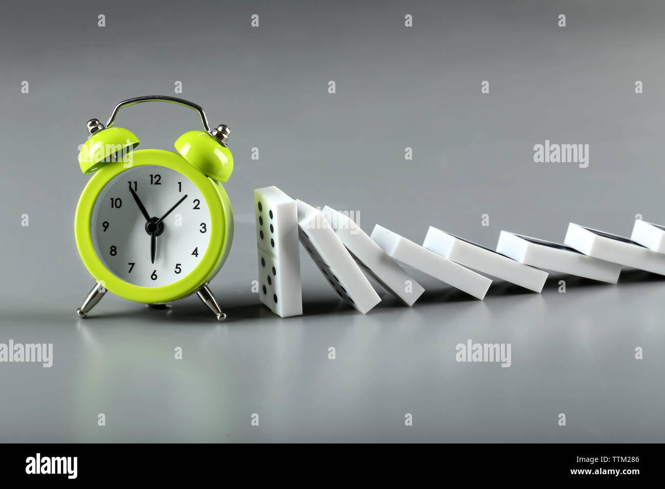 Dominoes and alarm clock on grey background Stock Photo - Alamy