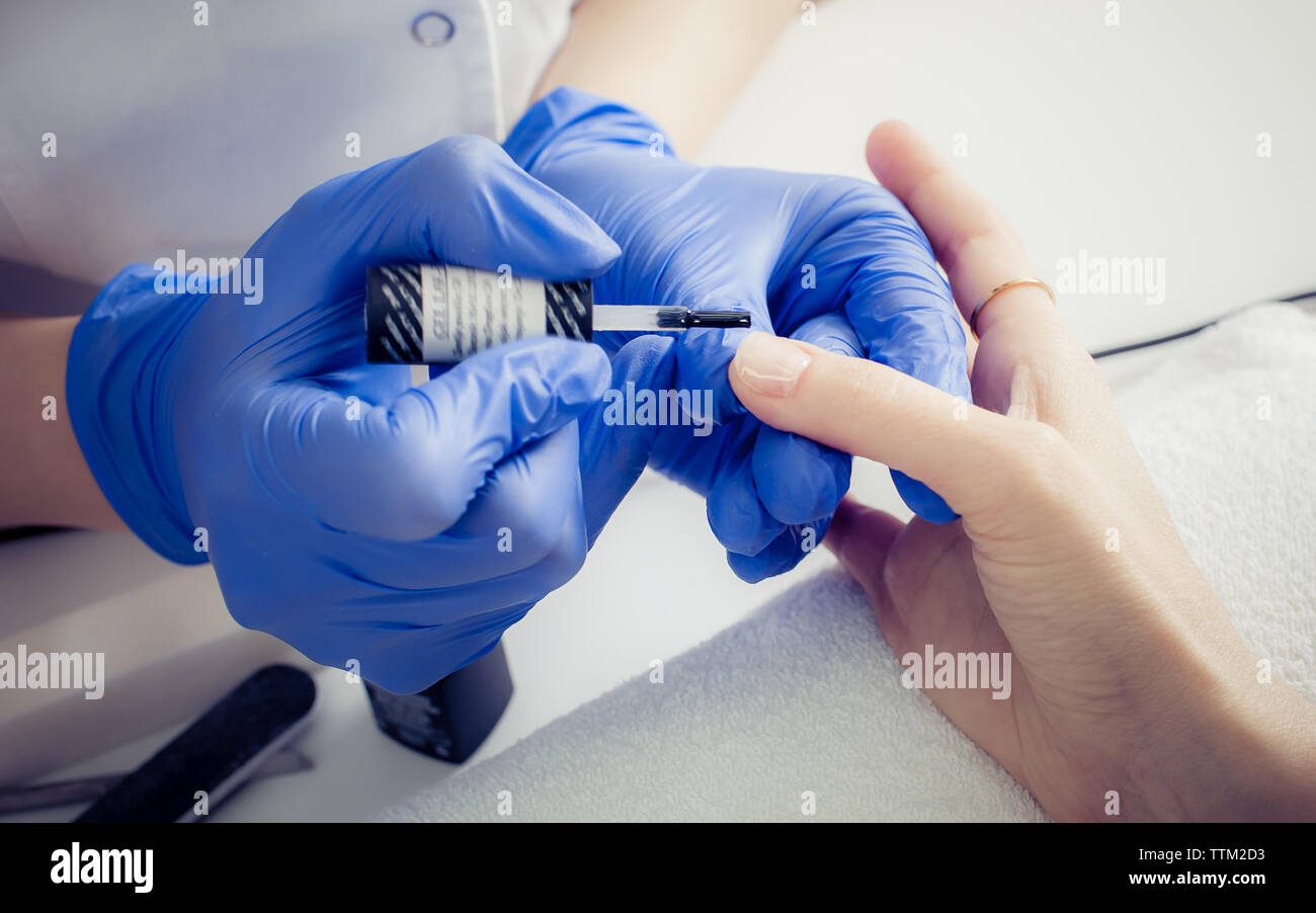 Female manicurist master applying colorless polish in beauty salon ...