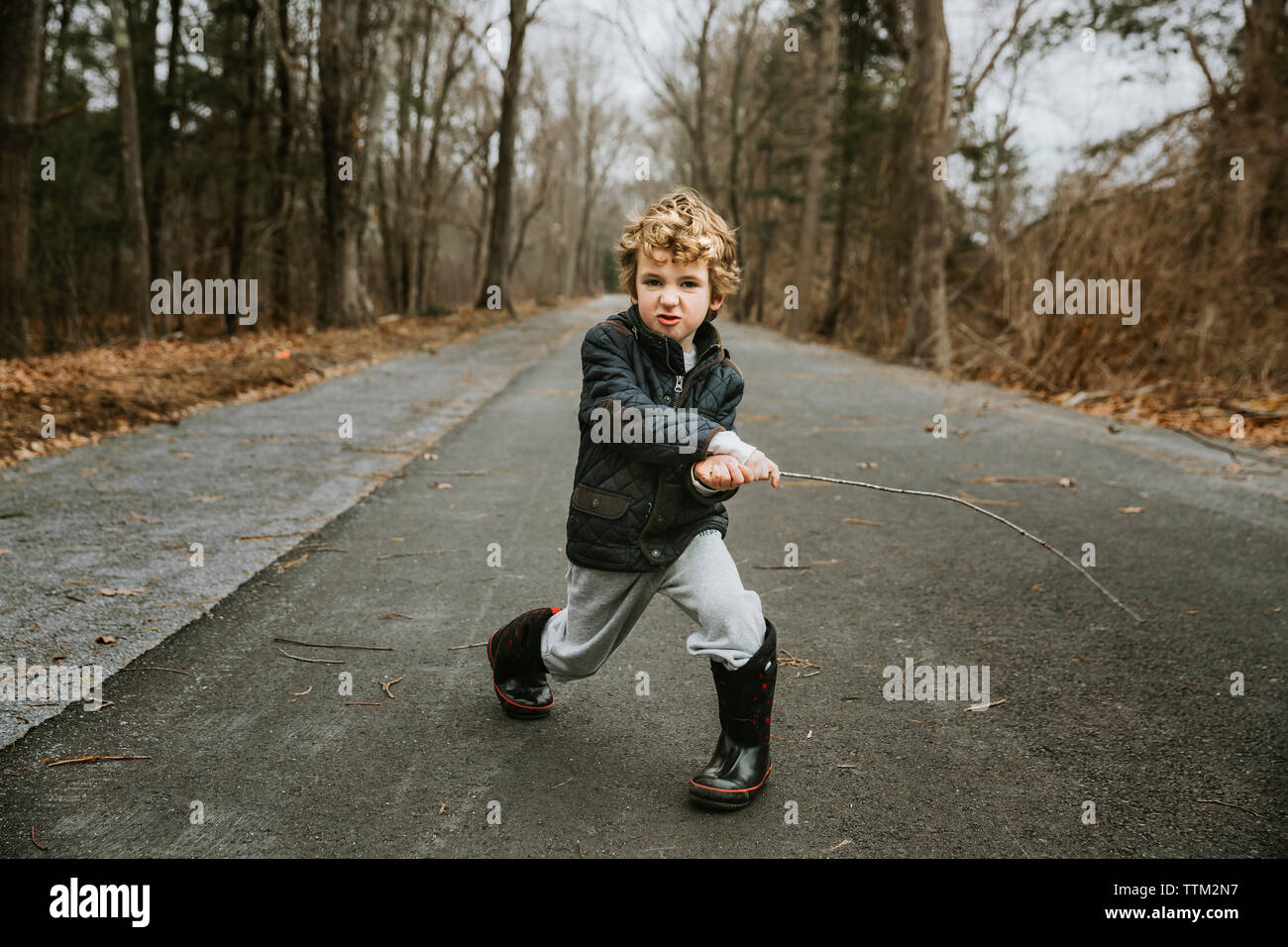 Full length portrait of cute boy playing with stick on road Stock Photo ...