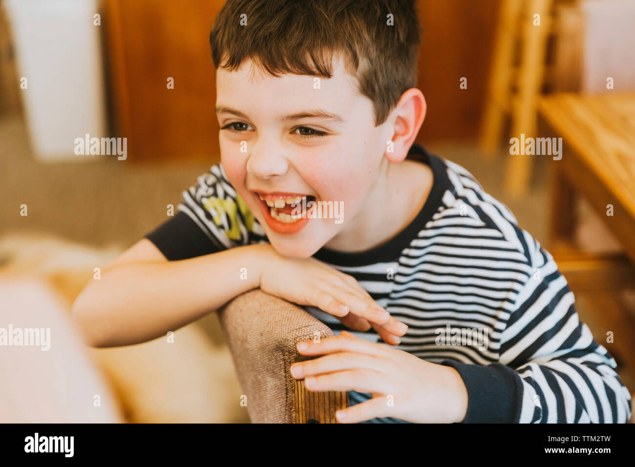 High angle view of cute happy boy laughing while sitting on chair at ...