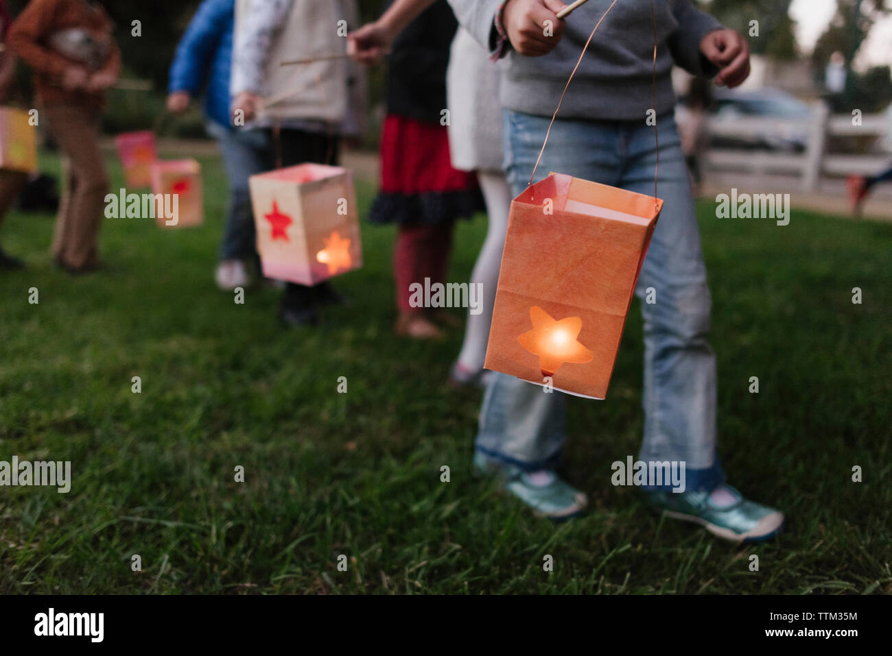Low section of children carrying illuminated paper lanterns while ...