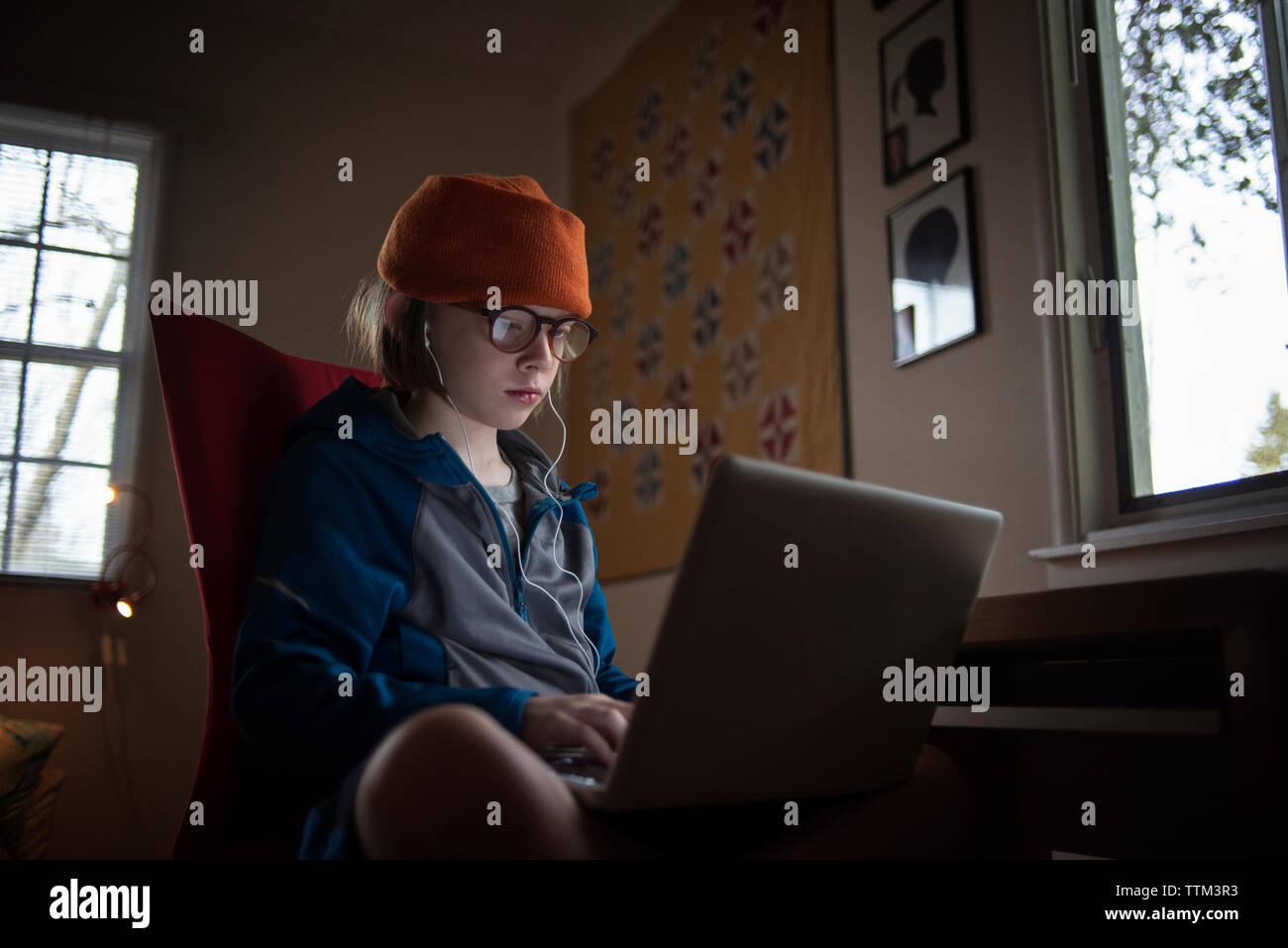 Boy using laptop computer while sitting on chair by table at home Stock ...
