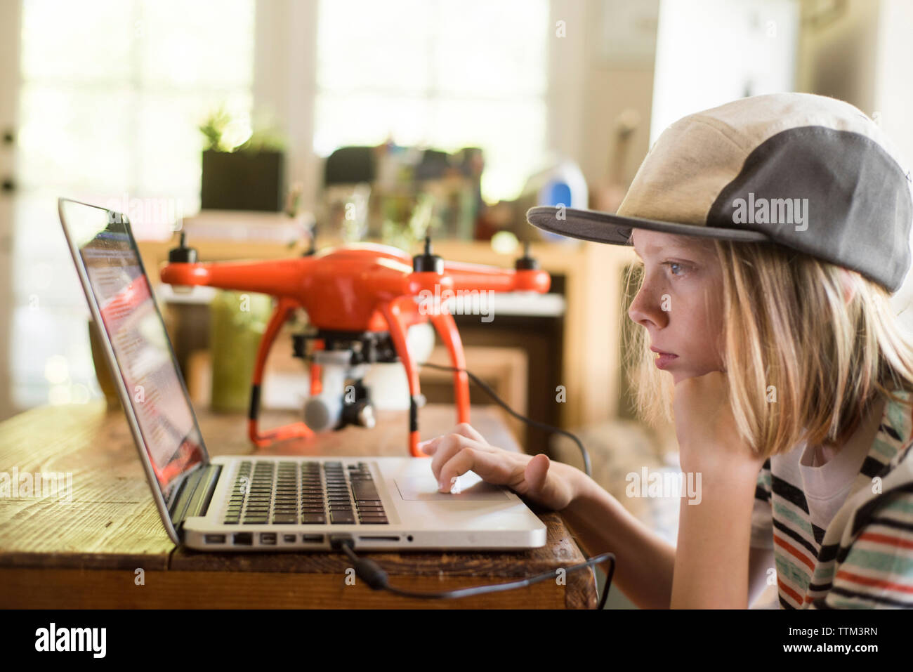 Side view of boy working on laptop computer by drone at home Stock ...