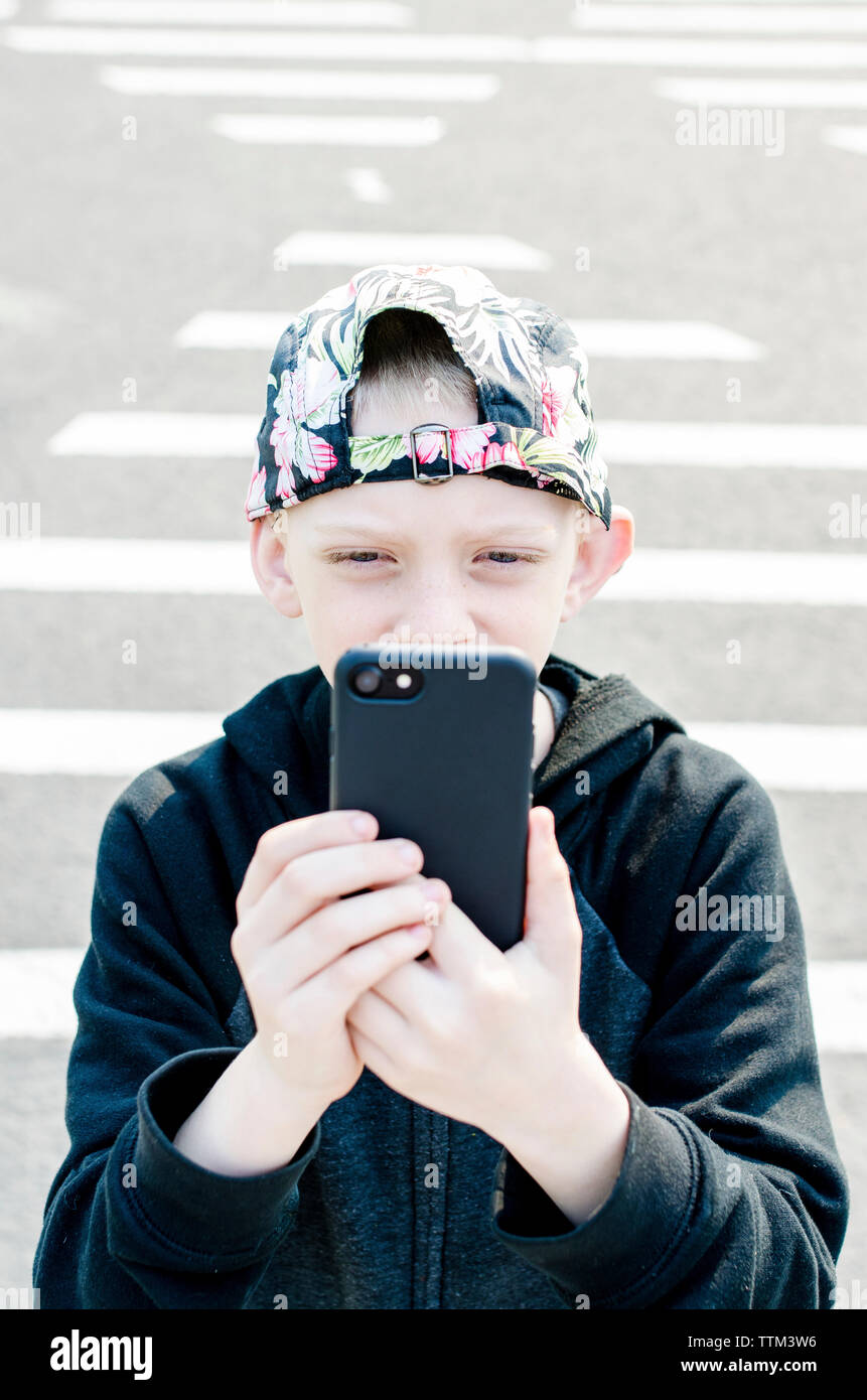 Boy looking at mobile phone standing hi-res stock photography and ...