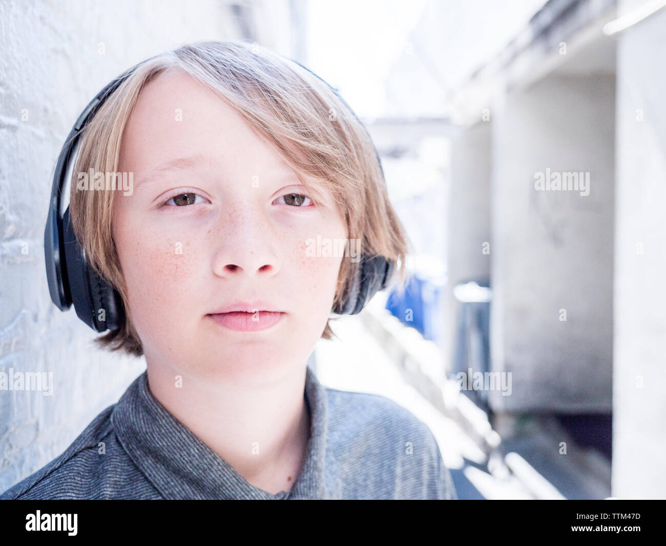 Close-up portrait of boy listening music while standing by wall Stock ...