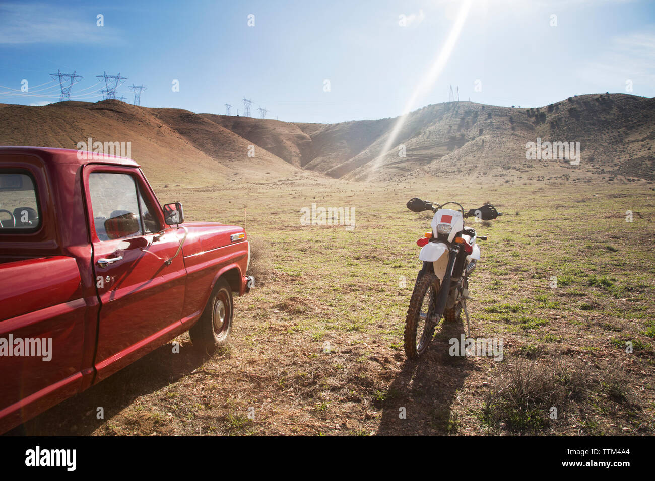 Motorcycle and pick-up truck on arid landscape against sky Stock Photo ...